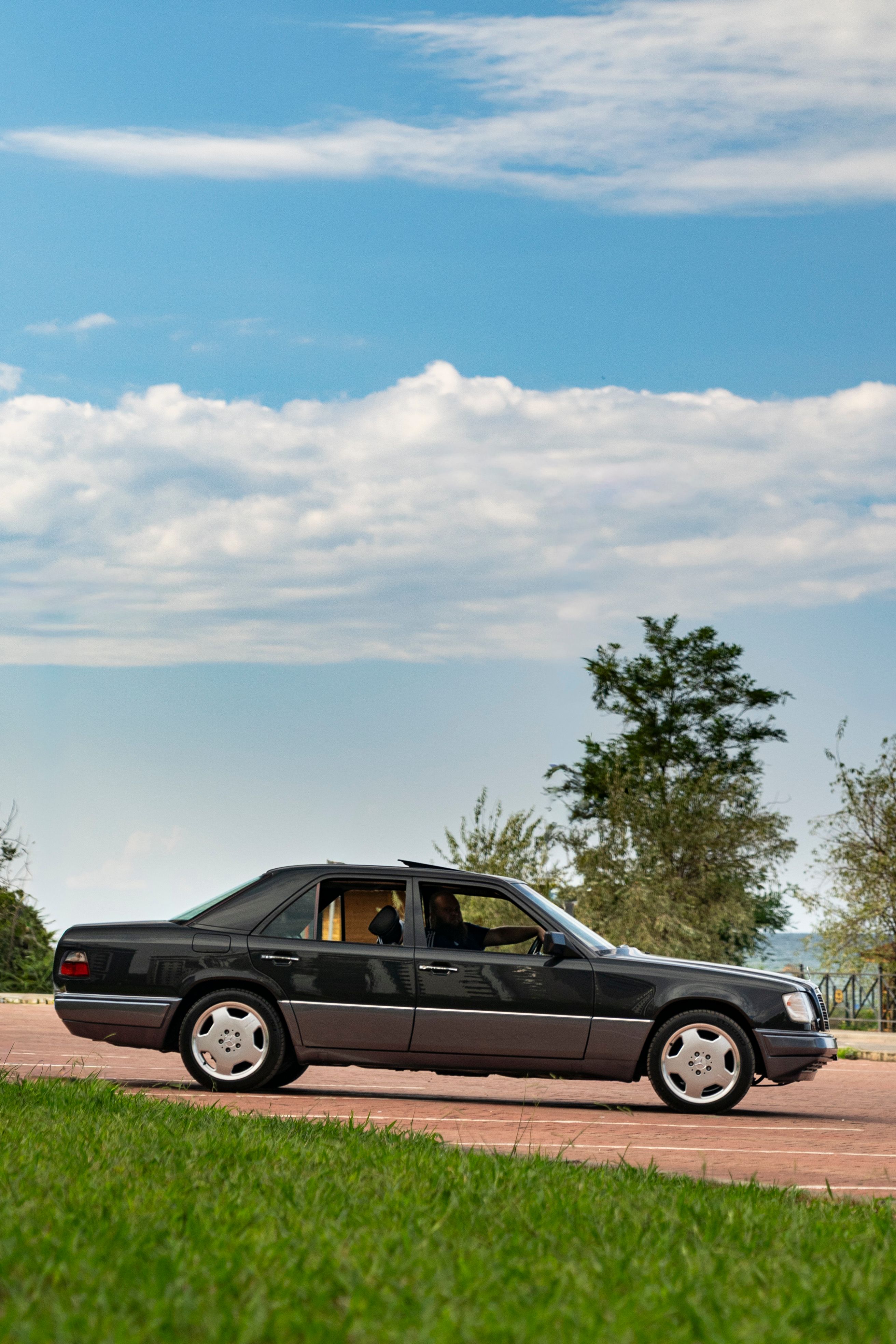 Classic Black Sedan on Open Road with Blue Sky · Free Stock Photo