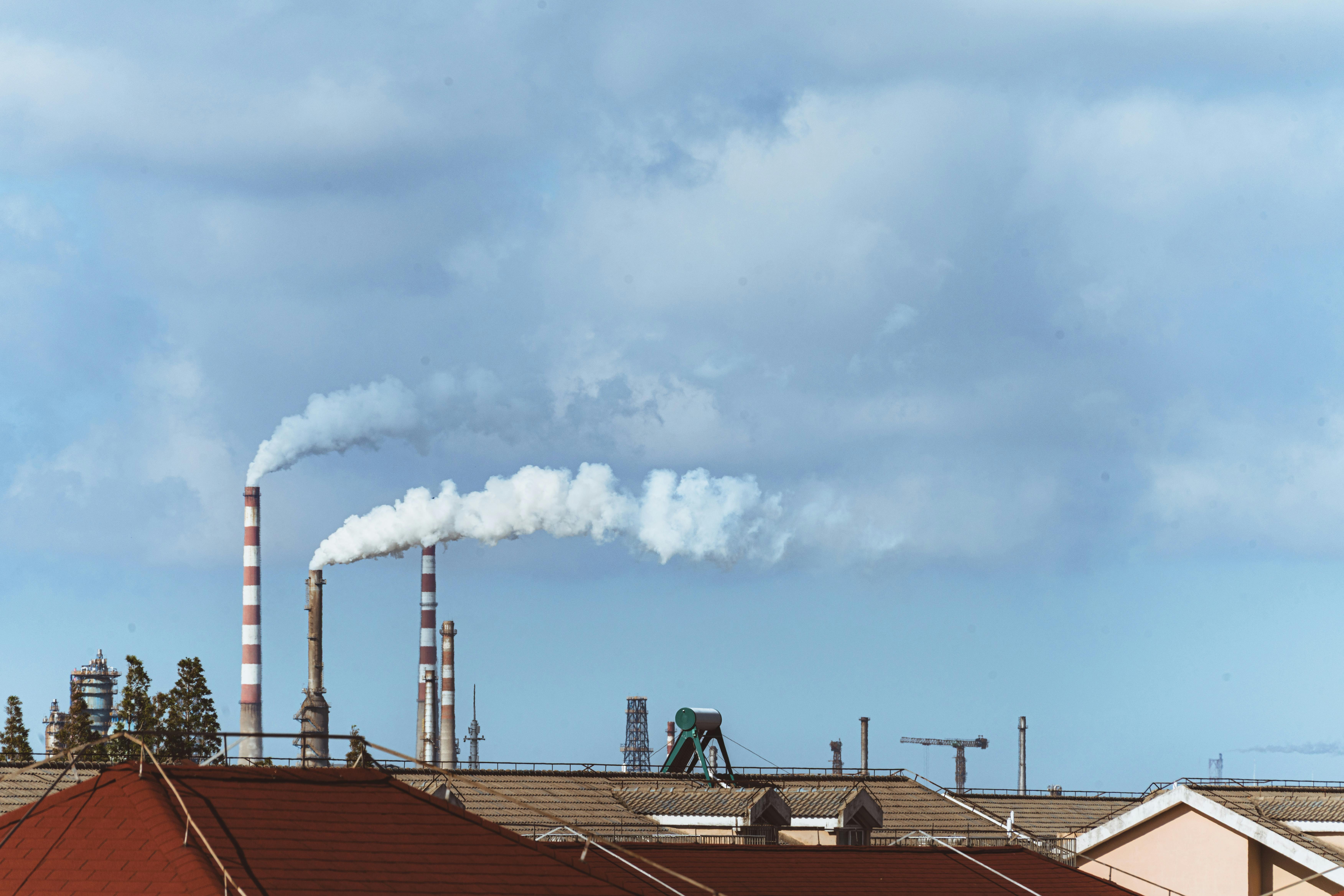Industrial Factory Emissions Against Urban Skyline · Free Stock Photo