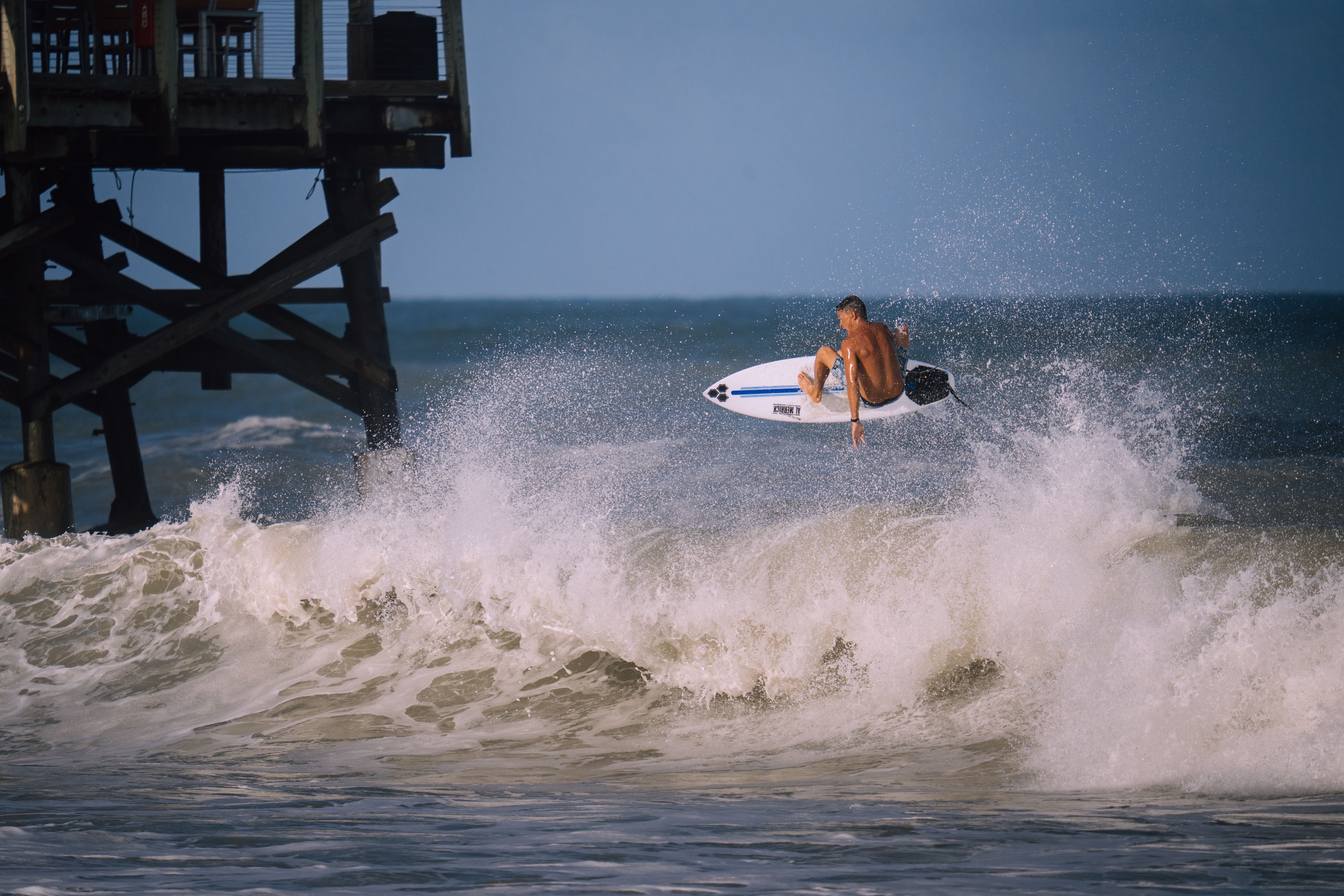 Dynamic Surfing Action Near Ocean Pier · Free Stock Photo