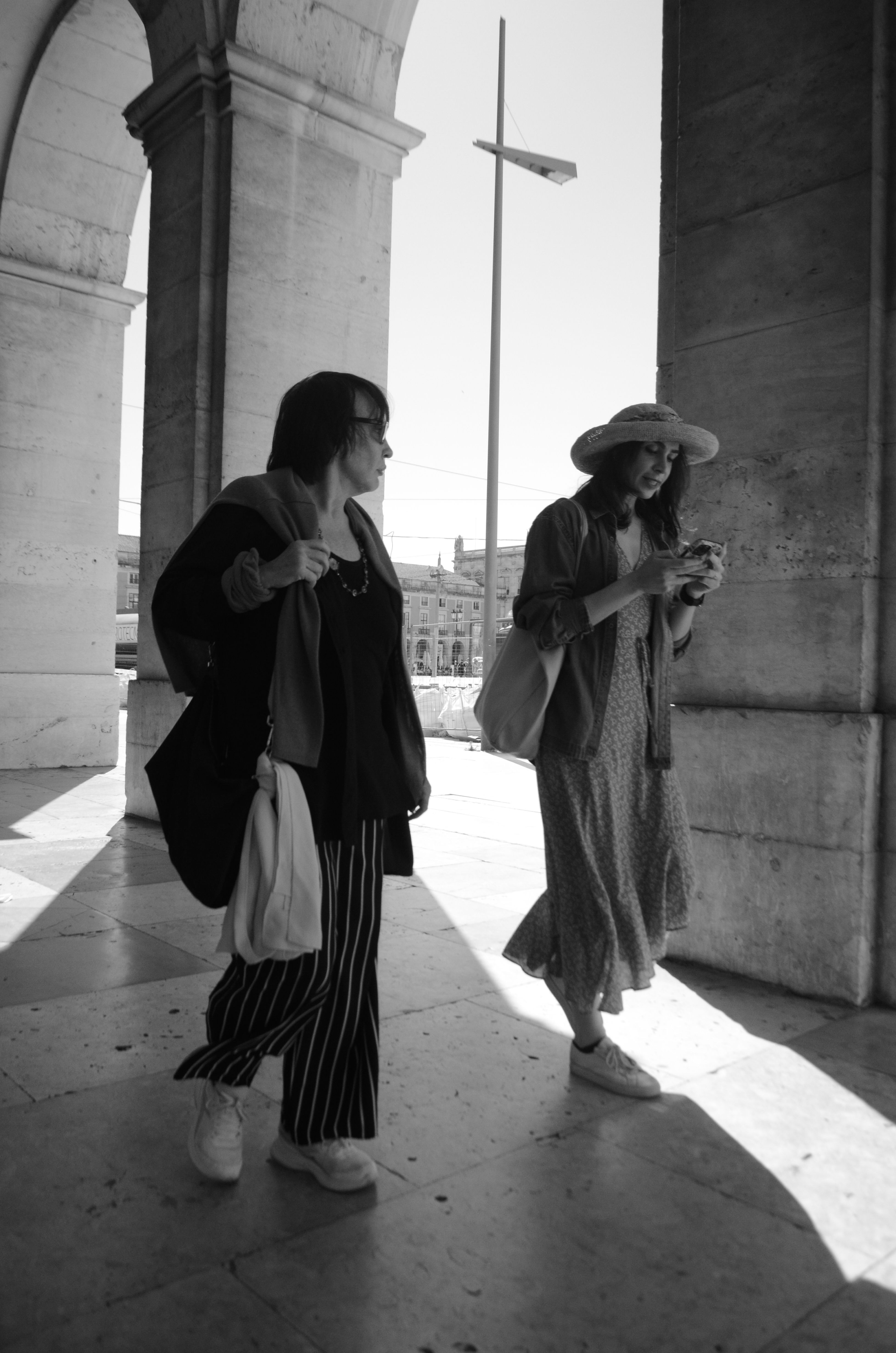 Stylish Women Enjoy Urban Exploration in Sunlit Archway · Free Stock Photo