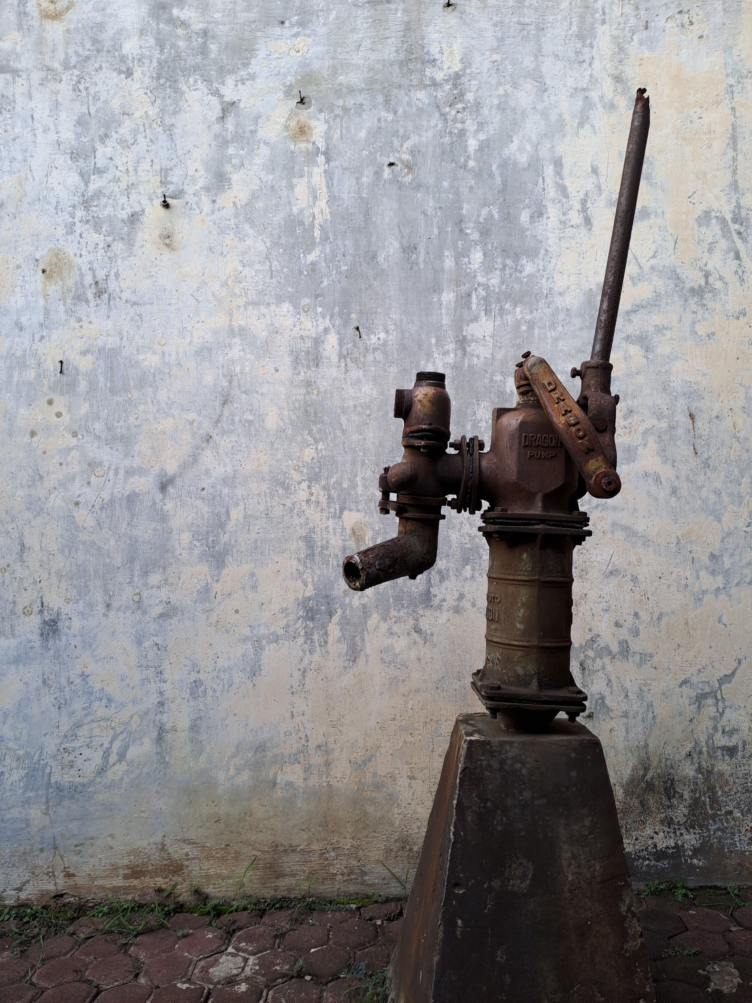 Vintage Rusted Water Pump Against Weathered Wall · Free Stock Photo