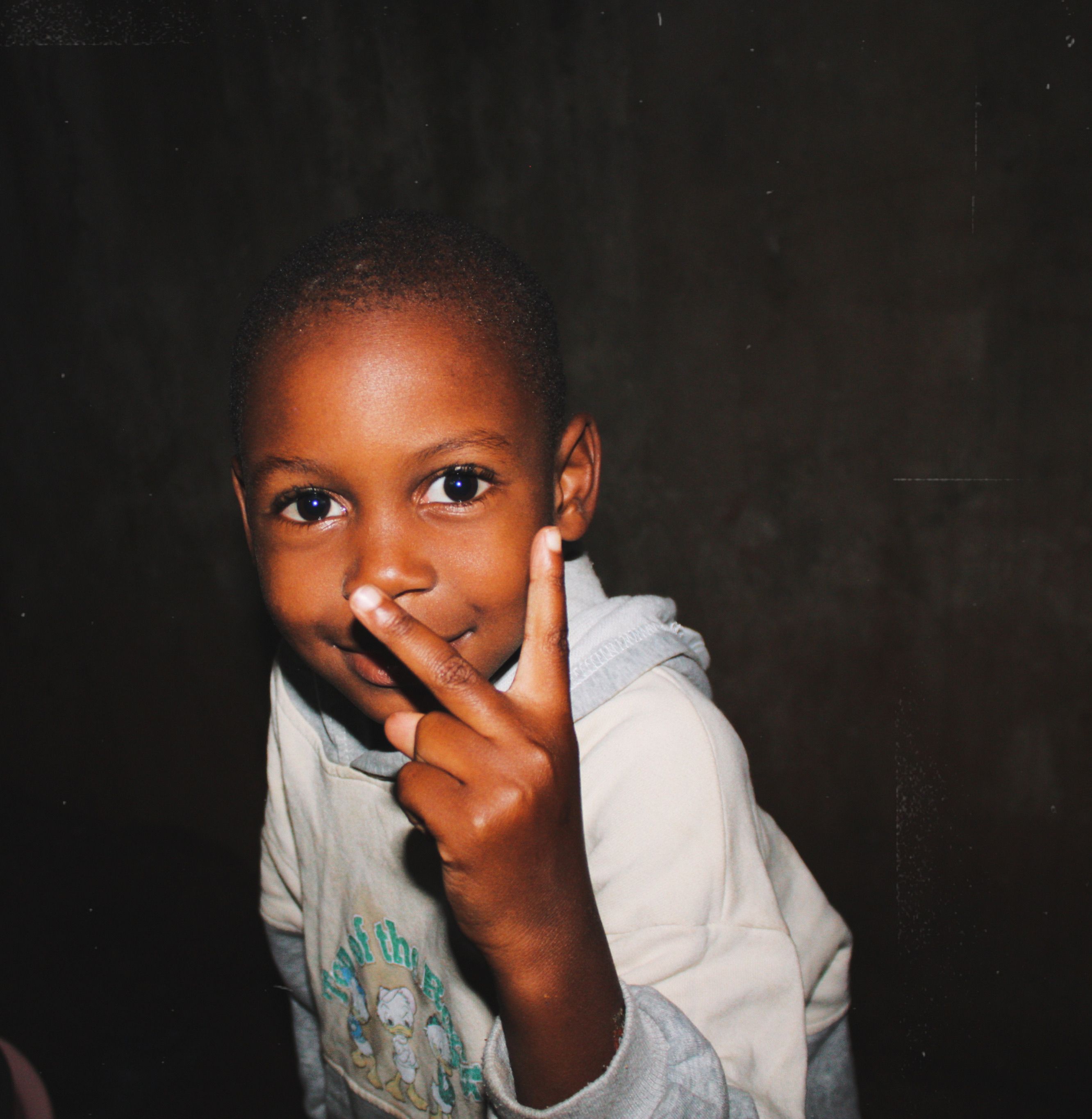 Smiling Child Making Peace Sign Indoors · Free Stock Photo