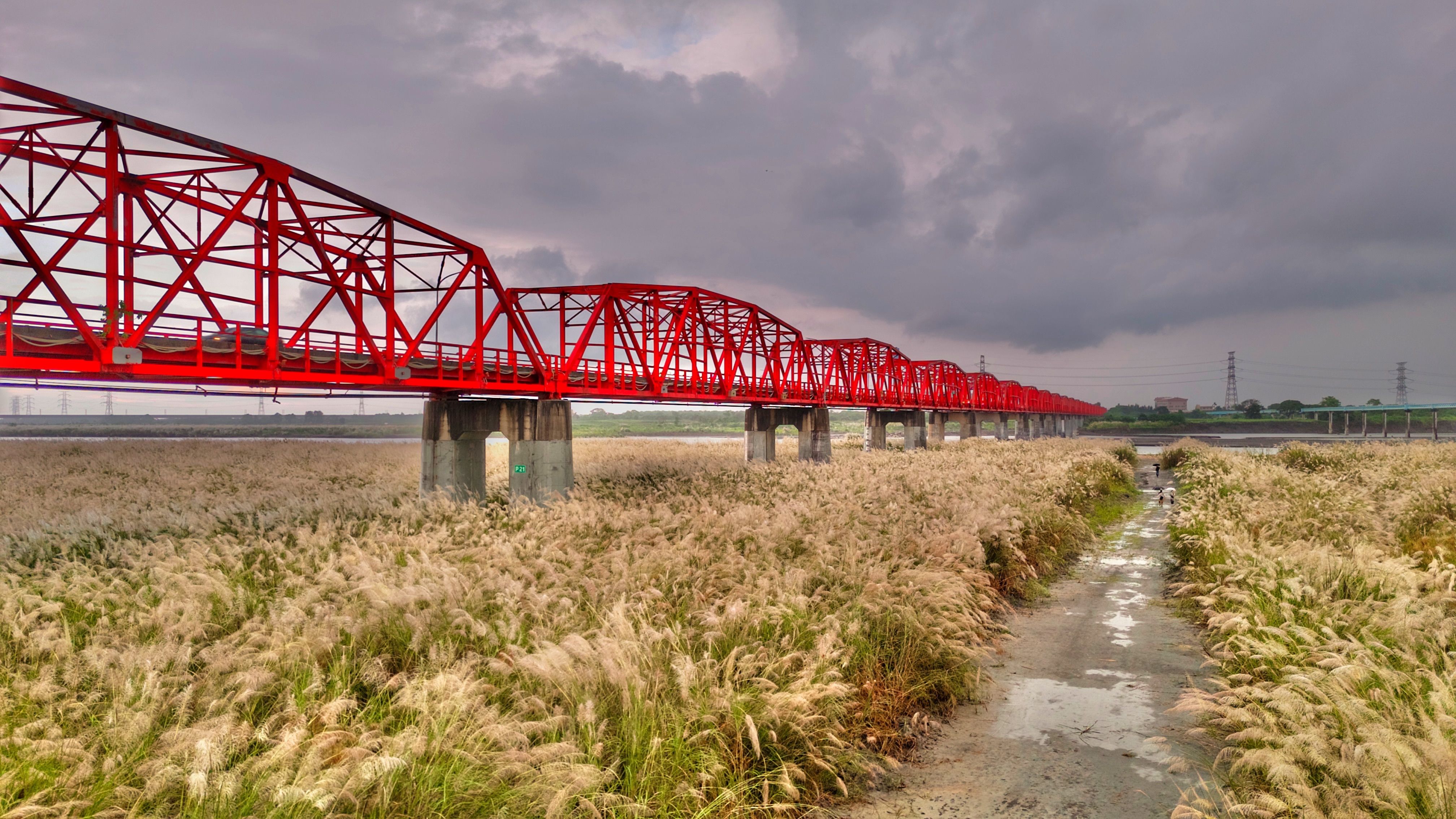 Red Steel Bridge Over Grassy Field at Dusk · Free Stock Photo