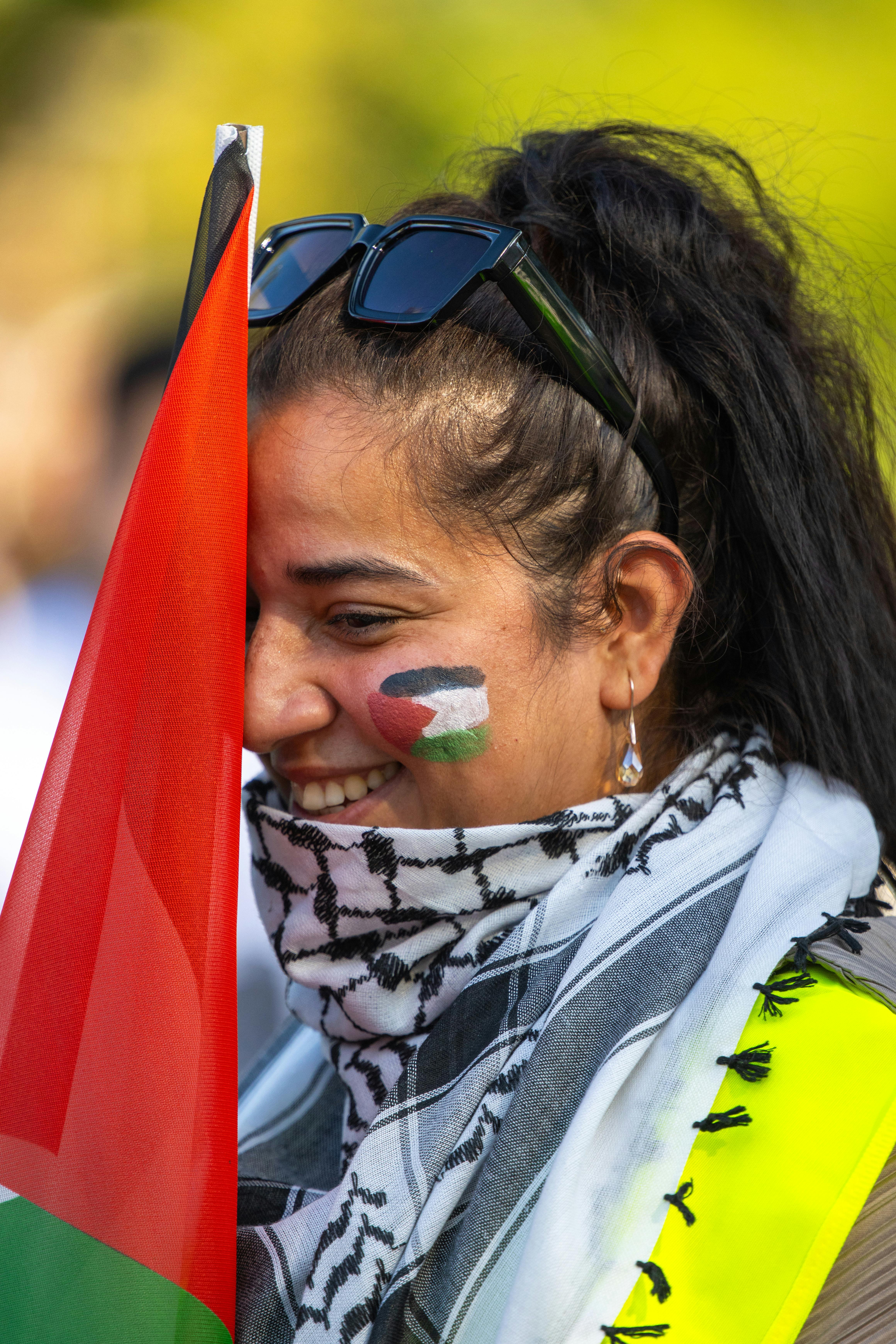 Smiling Woman Holding Palestinian Flag at Demonstration · Free Stock Photo