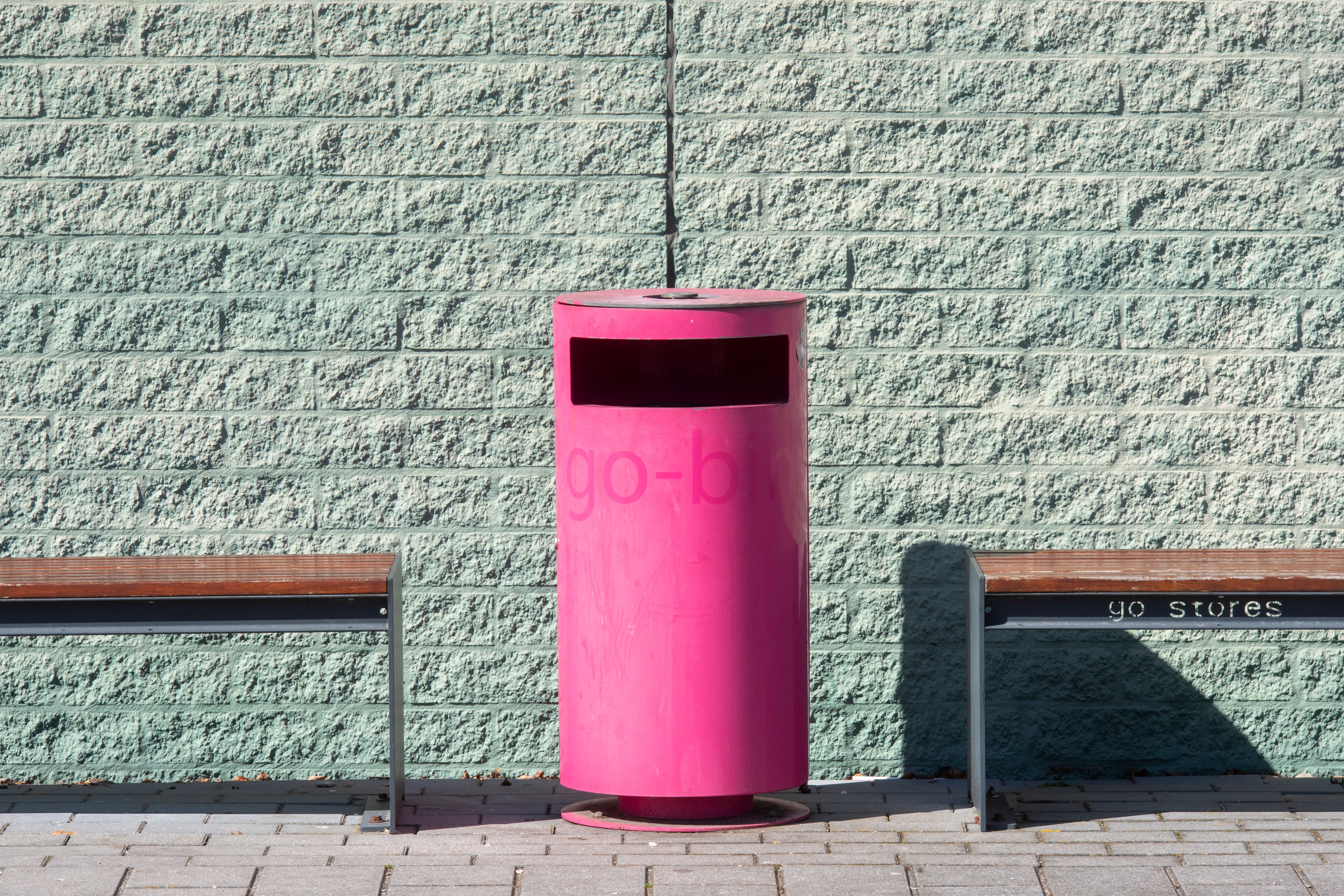 Vibrant Pink Trash Bin Against Textured Wall · Free Stock Photo