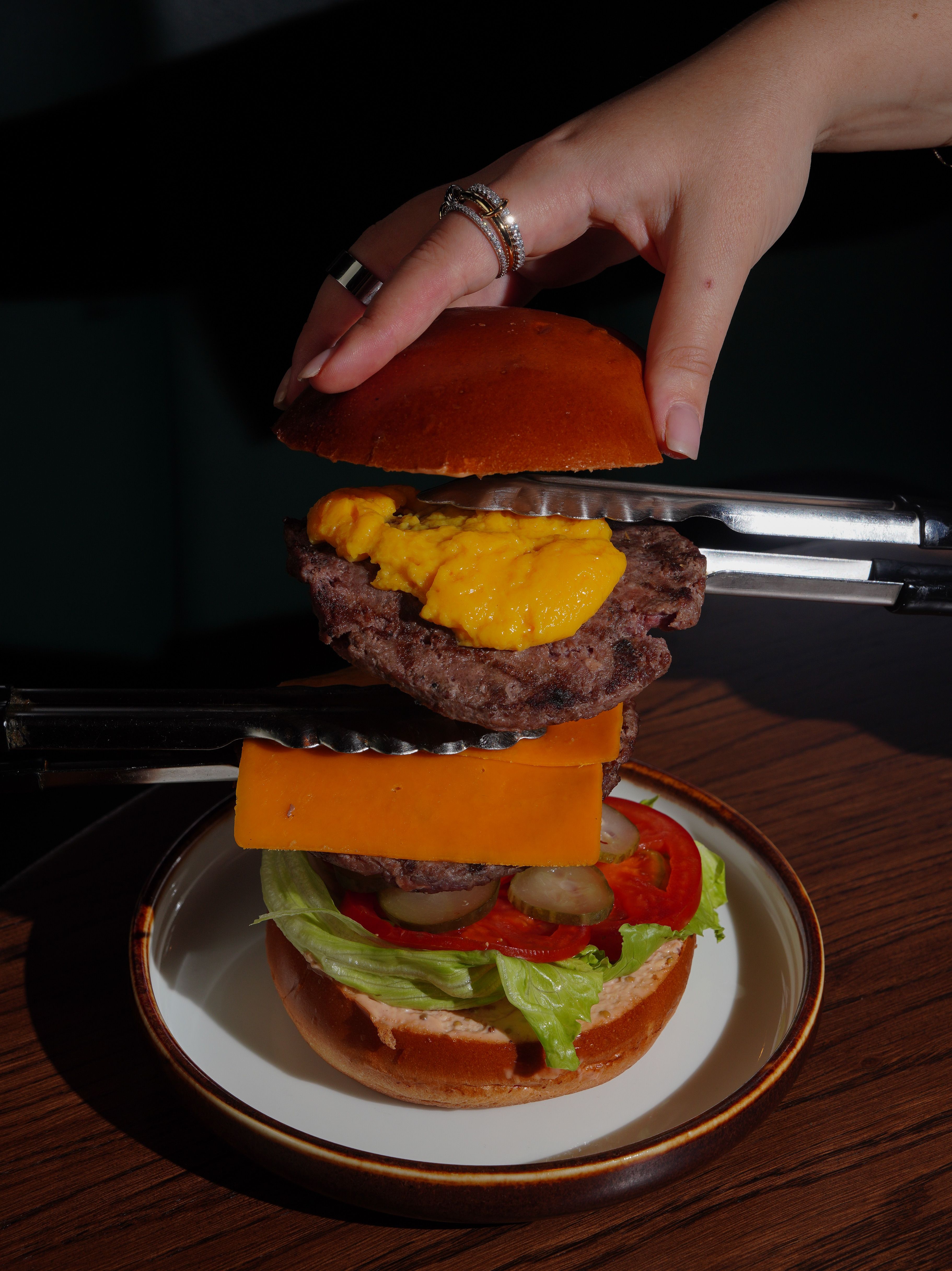 Close-up shot of gourmet burger being assembled · Free Stock Photo