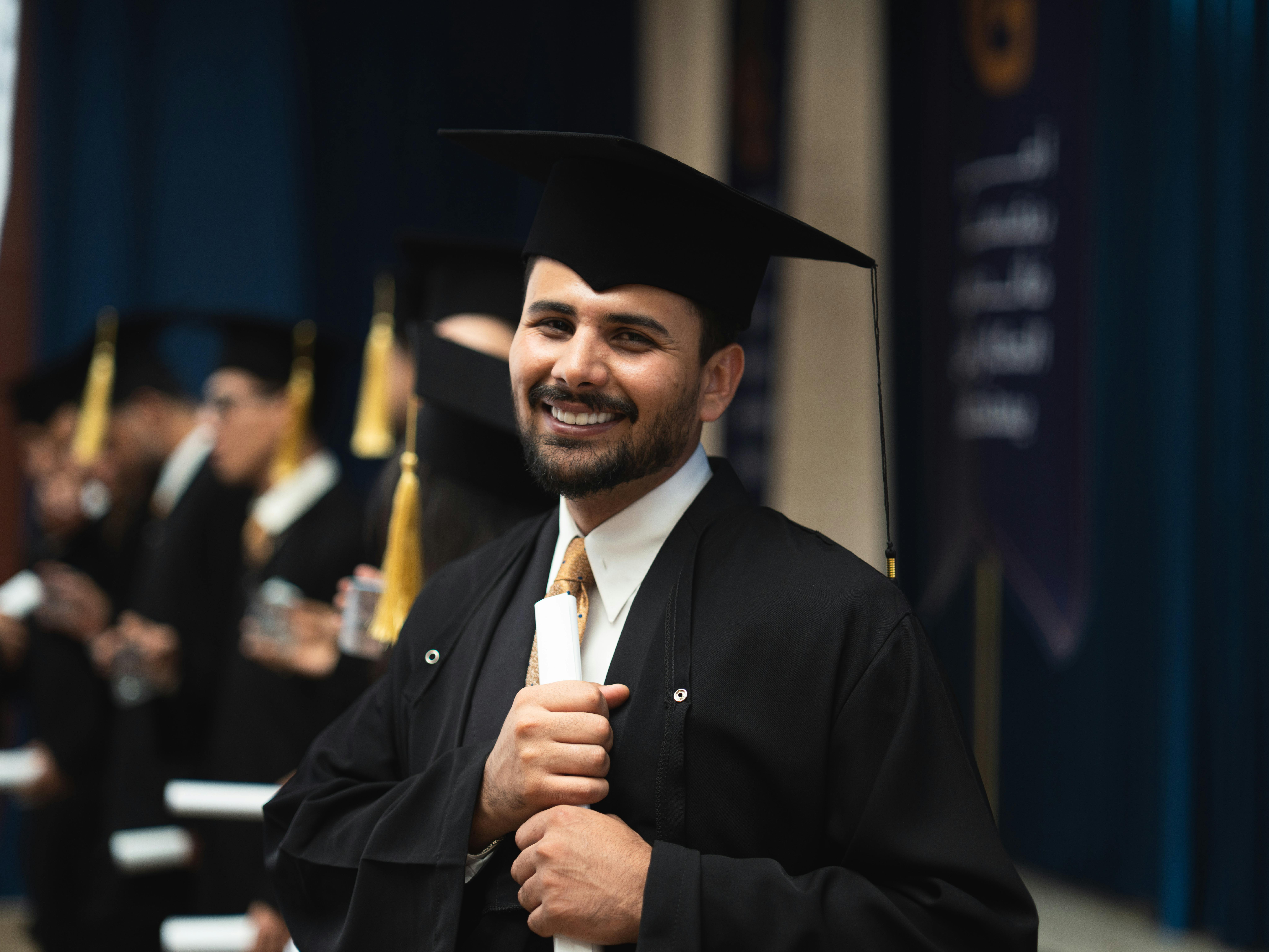 Smiling Graduate Holding Diploma at Ceremony · Free Stock Photo