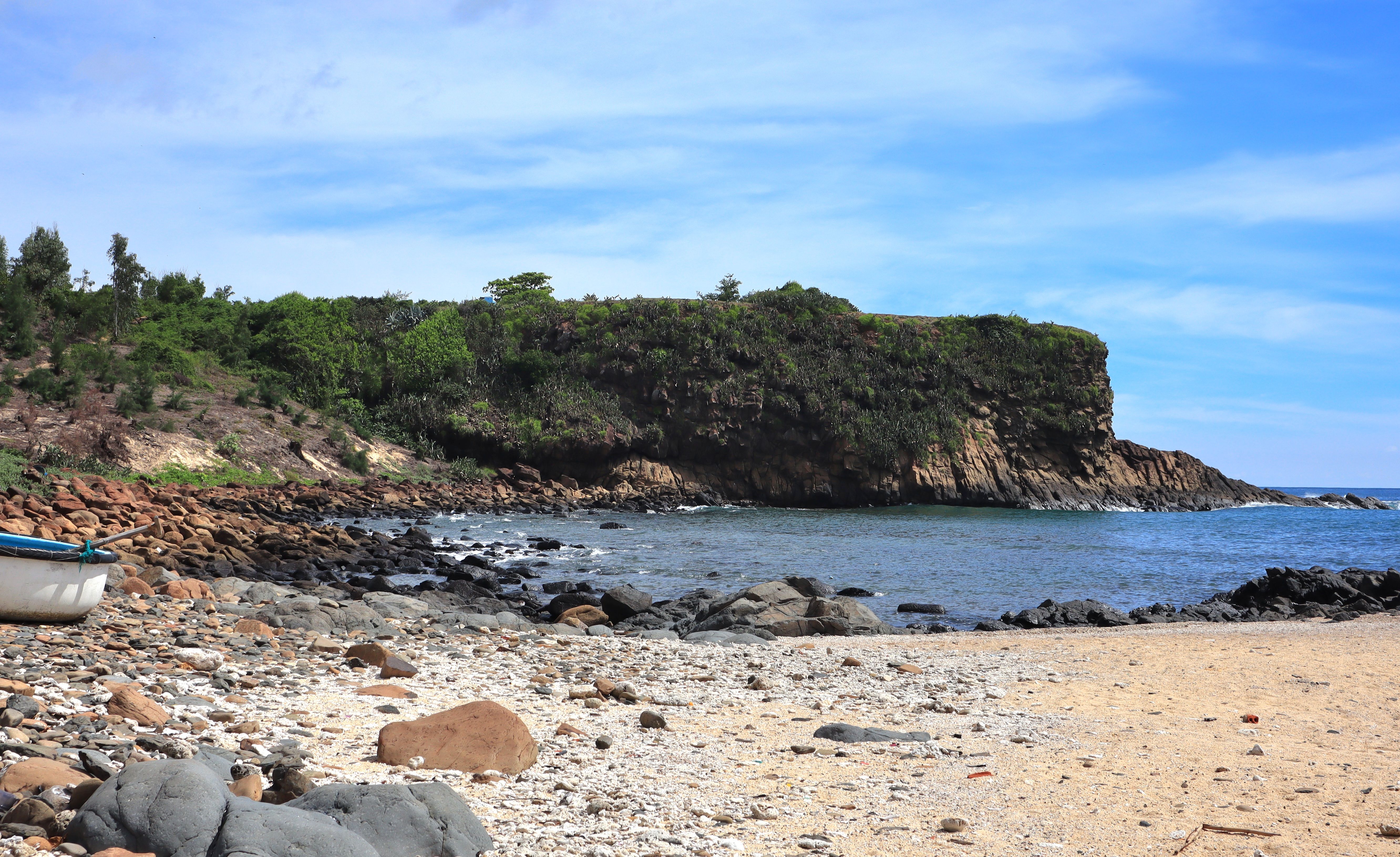 Rocky Beach with Cliff and Boat under Clear Sky · Free Stock Photo