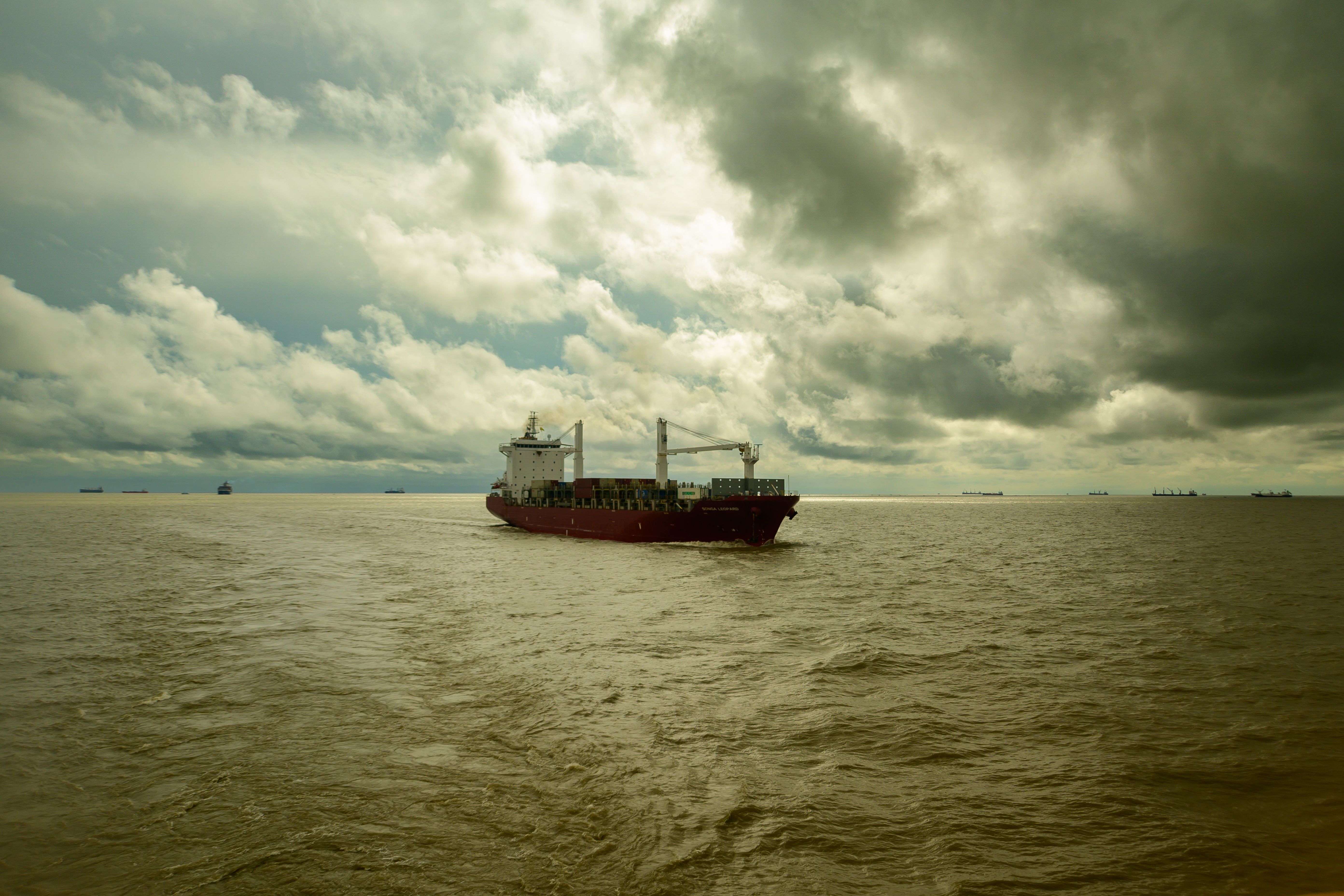 Cargo Ship on Open Sea Under Dramatic Sky · Free Stock Photo