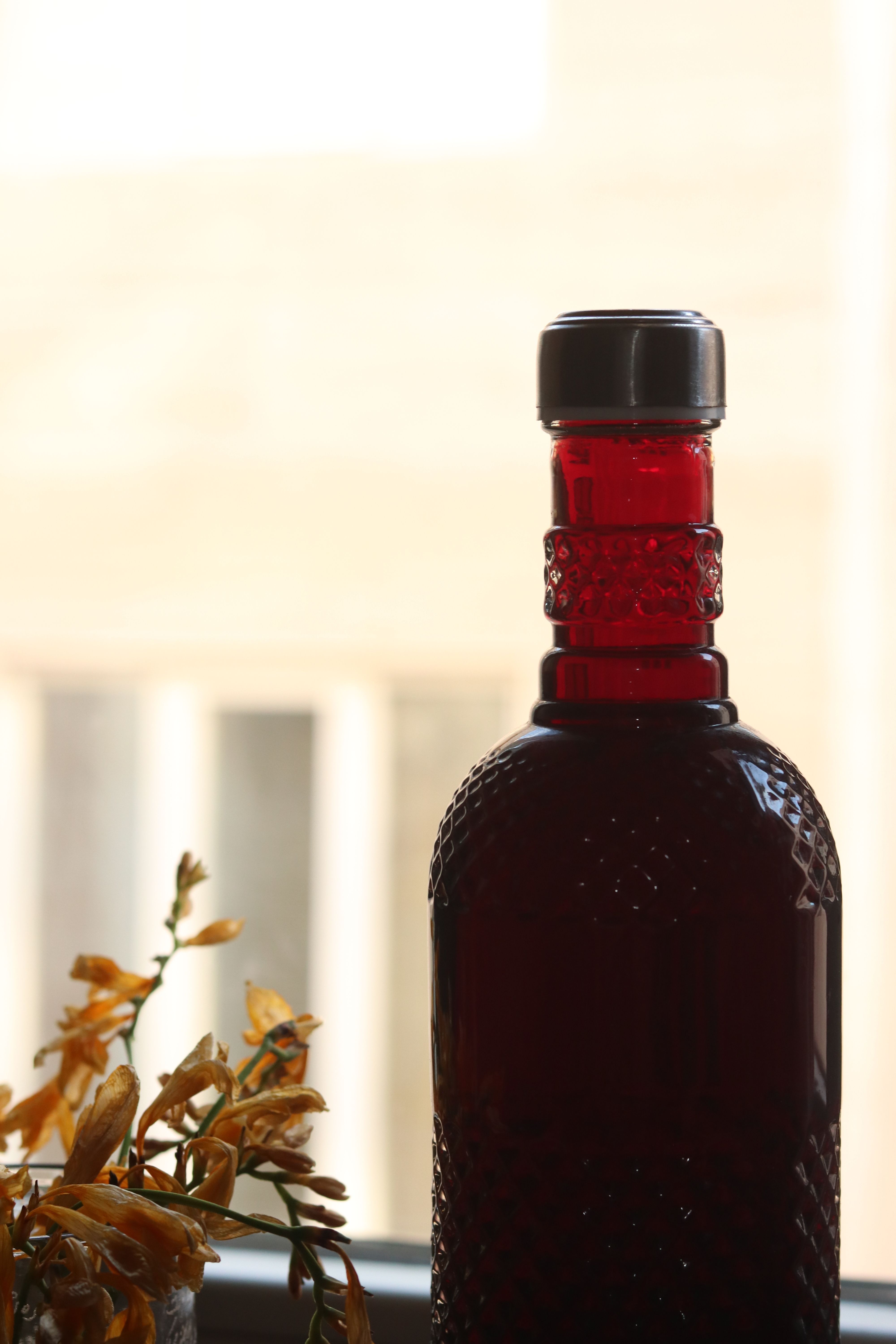 Elegant Red Glass Bottle with Floral Accent · Free Stock Photo