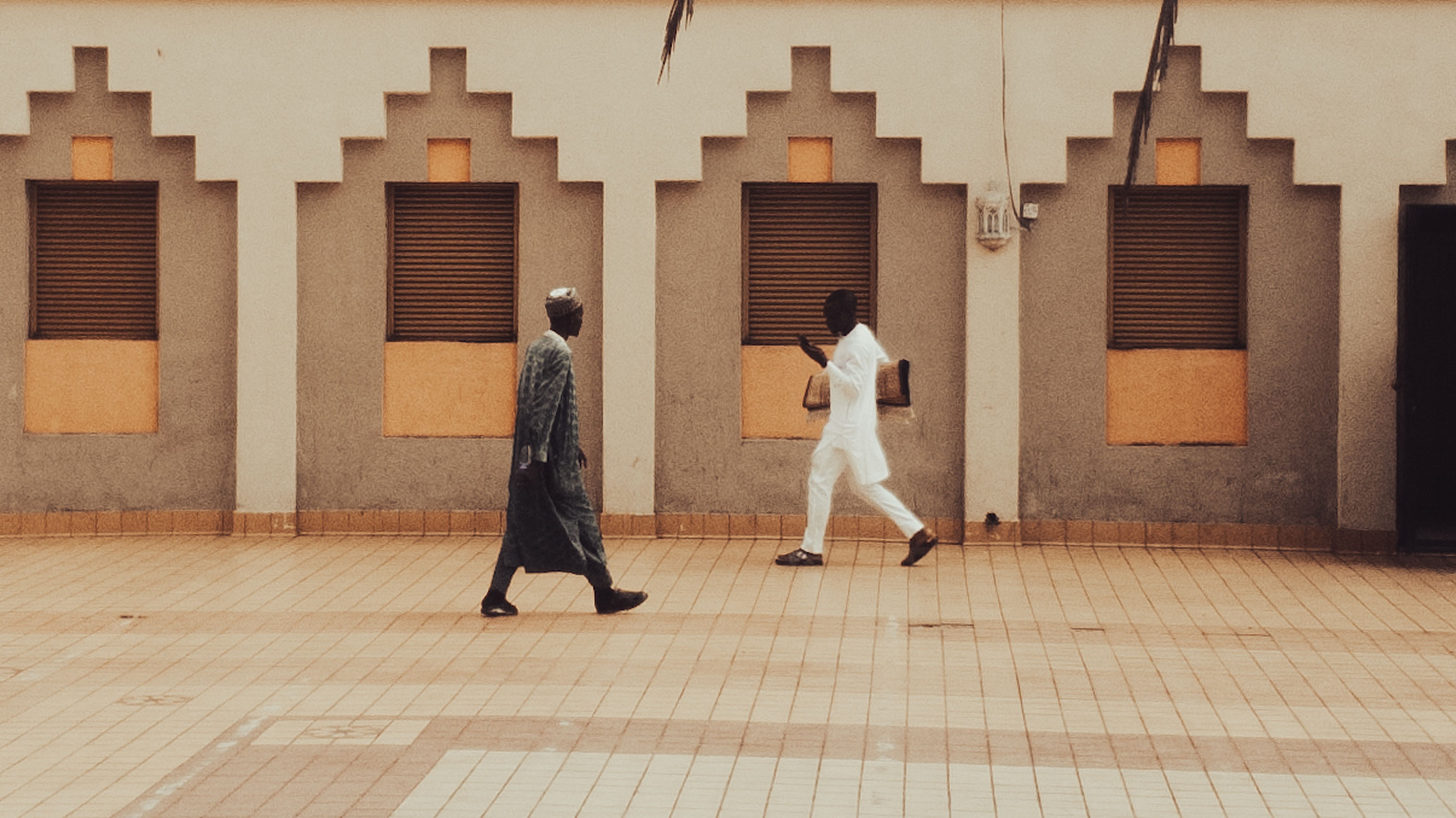 Two Men Walking in Front of Geometric Building · Free Stock Photo