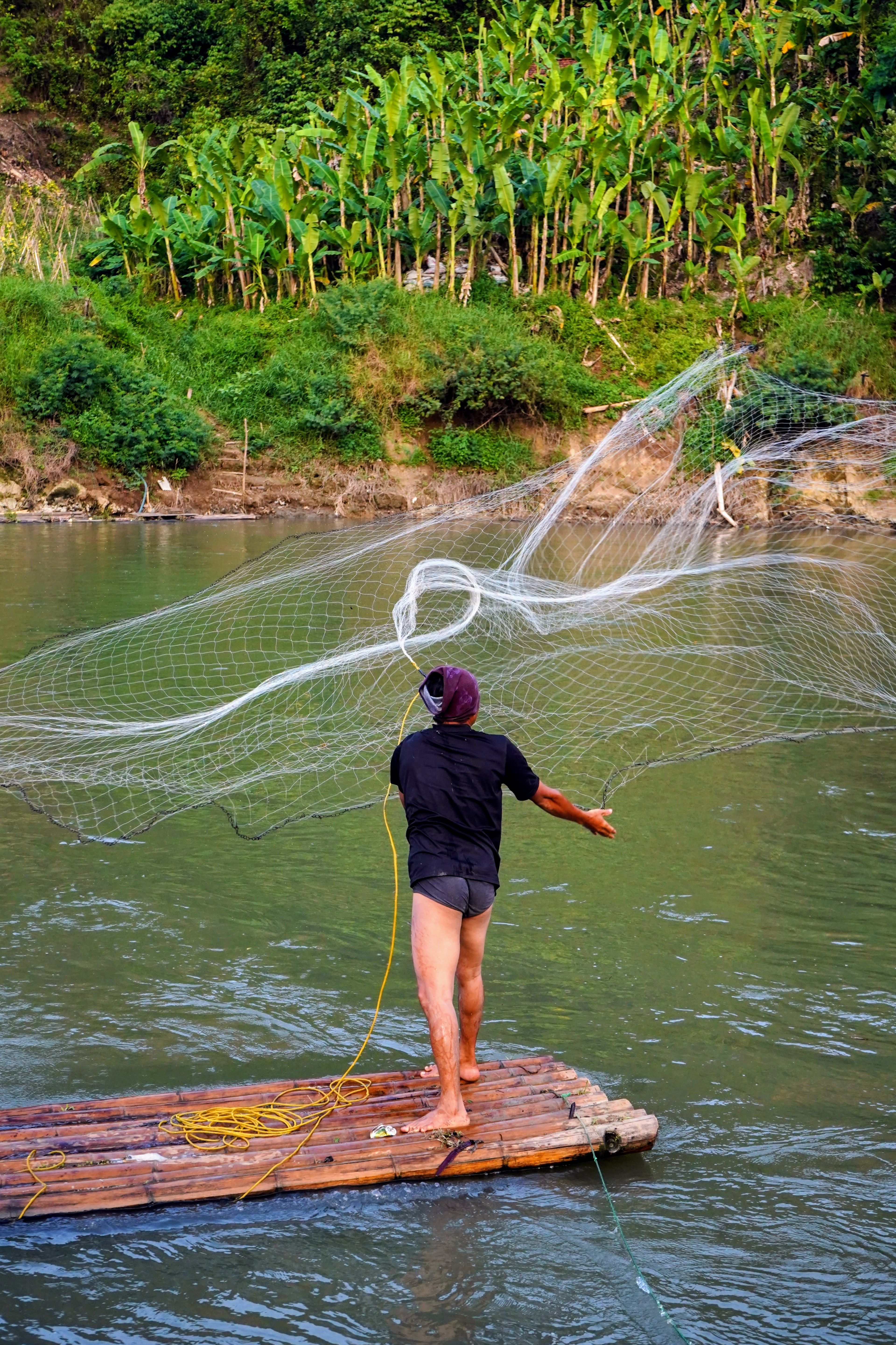 Fisherman Casting Net in Scenic West Java River · Free Stock Photo