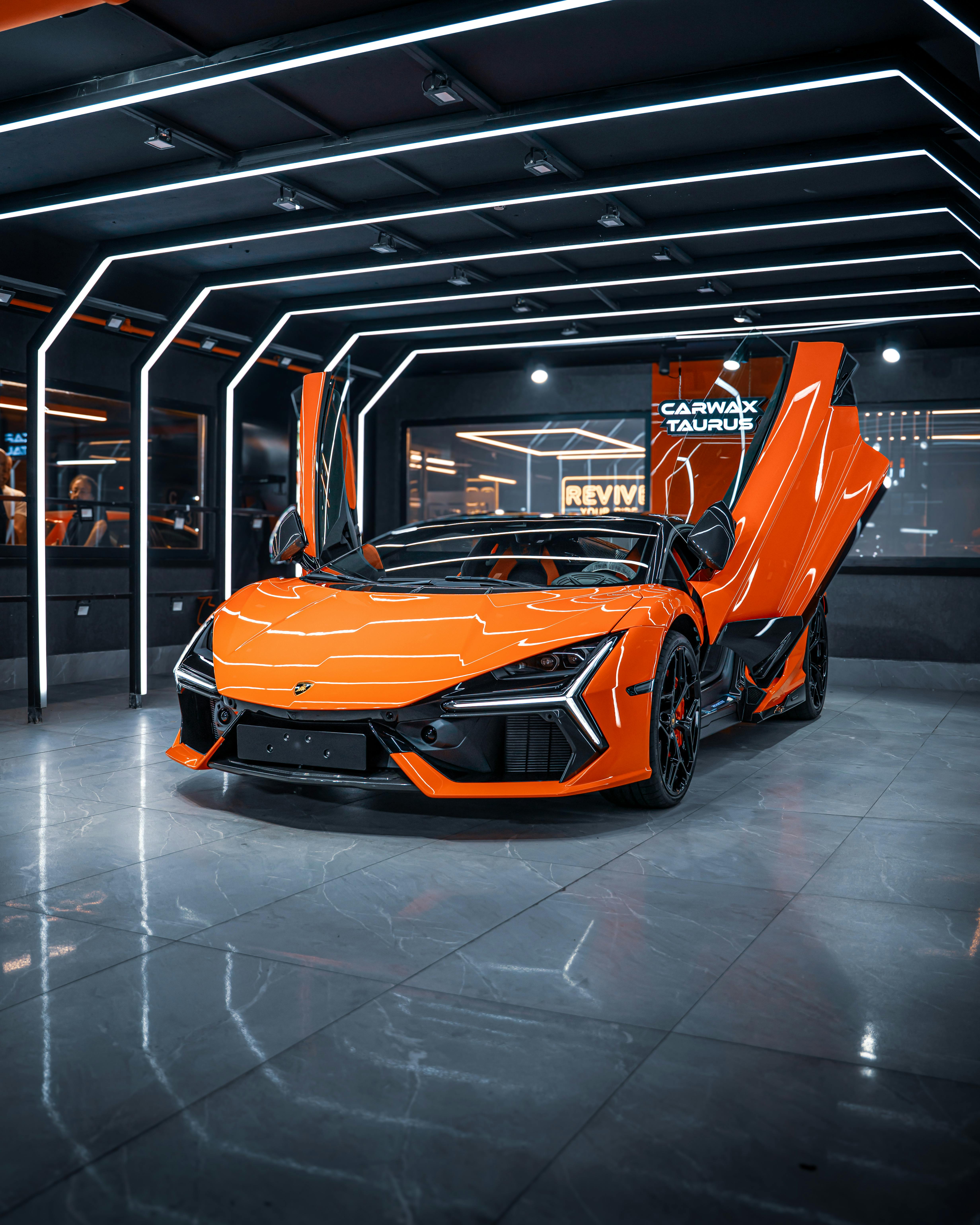 Sleek Orange Sports Car in Modern Indoor Showroom · Free Stock Photo