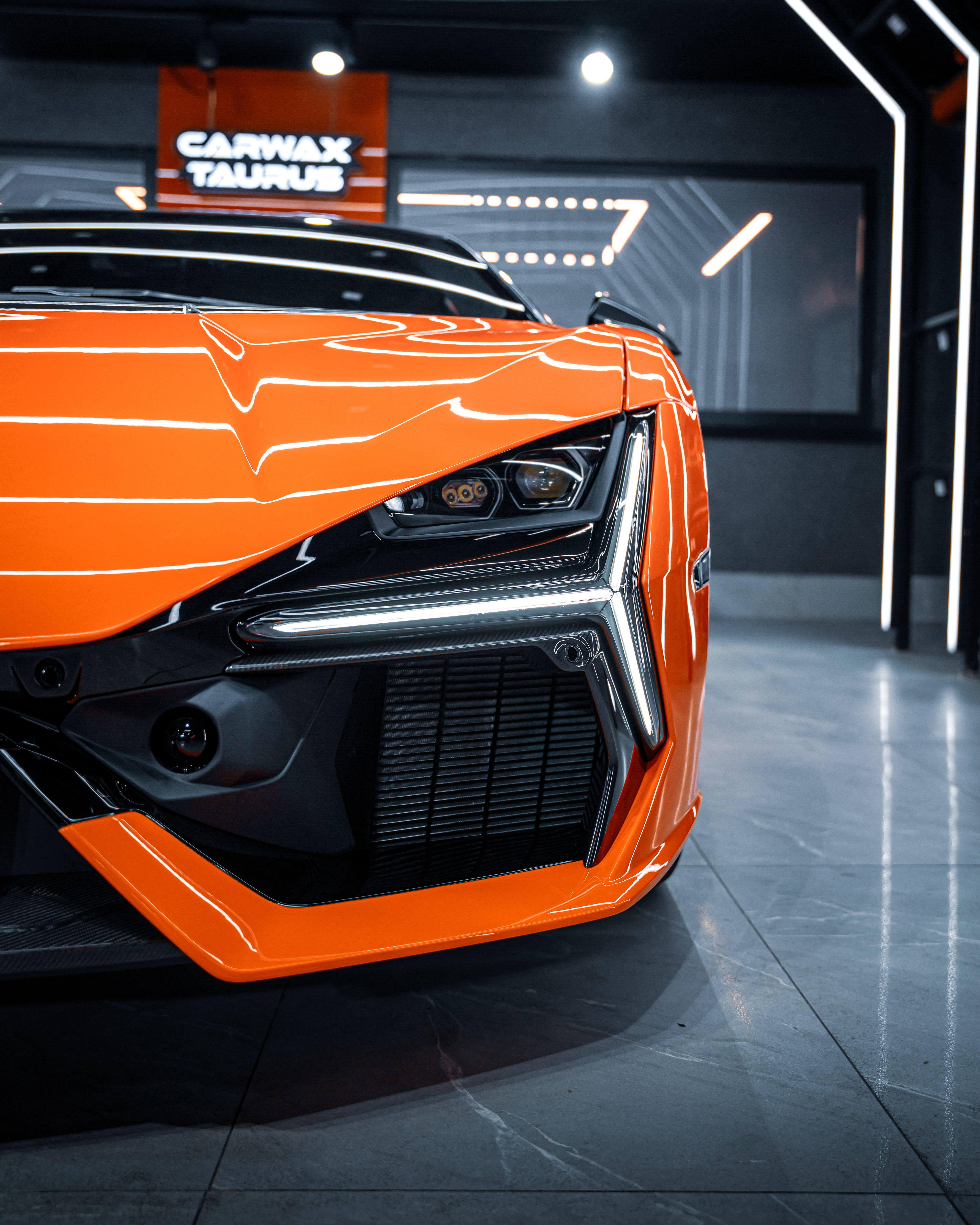 Sleek Orange Sports Car in Modern Indoor Showroom · Free Stock Photo