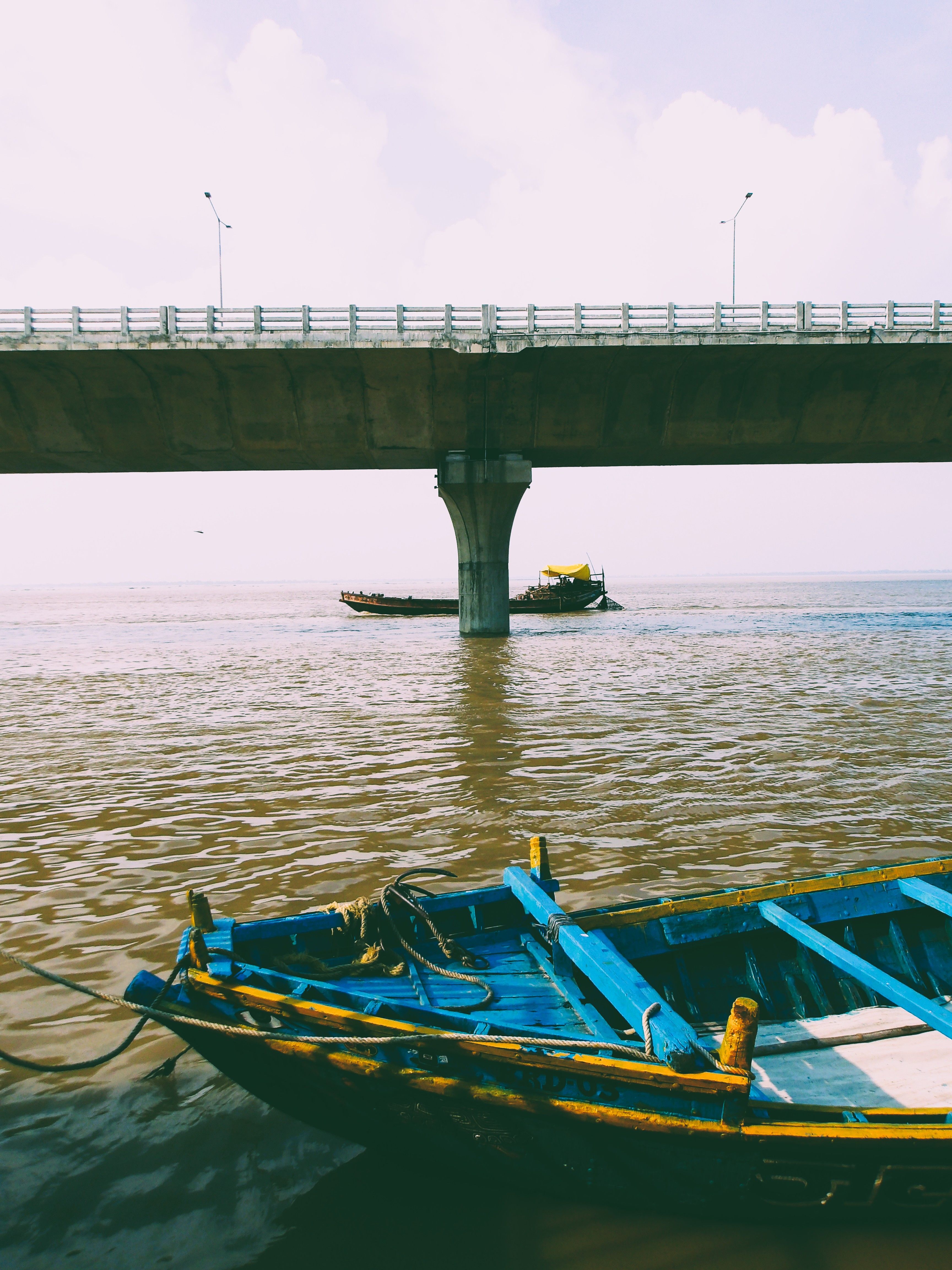 Serene Blue Boat Underneath Large Bridge · Free Stock Photo