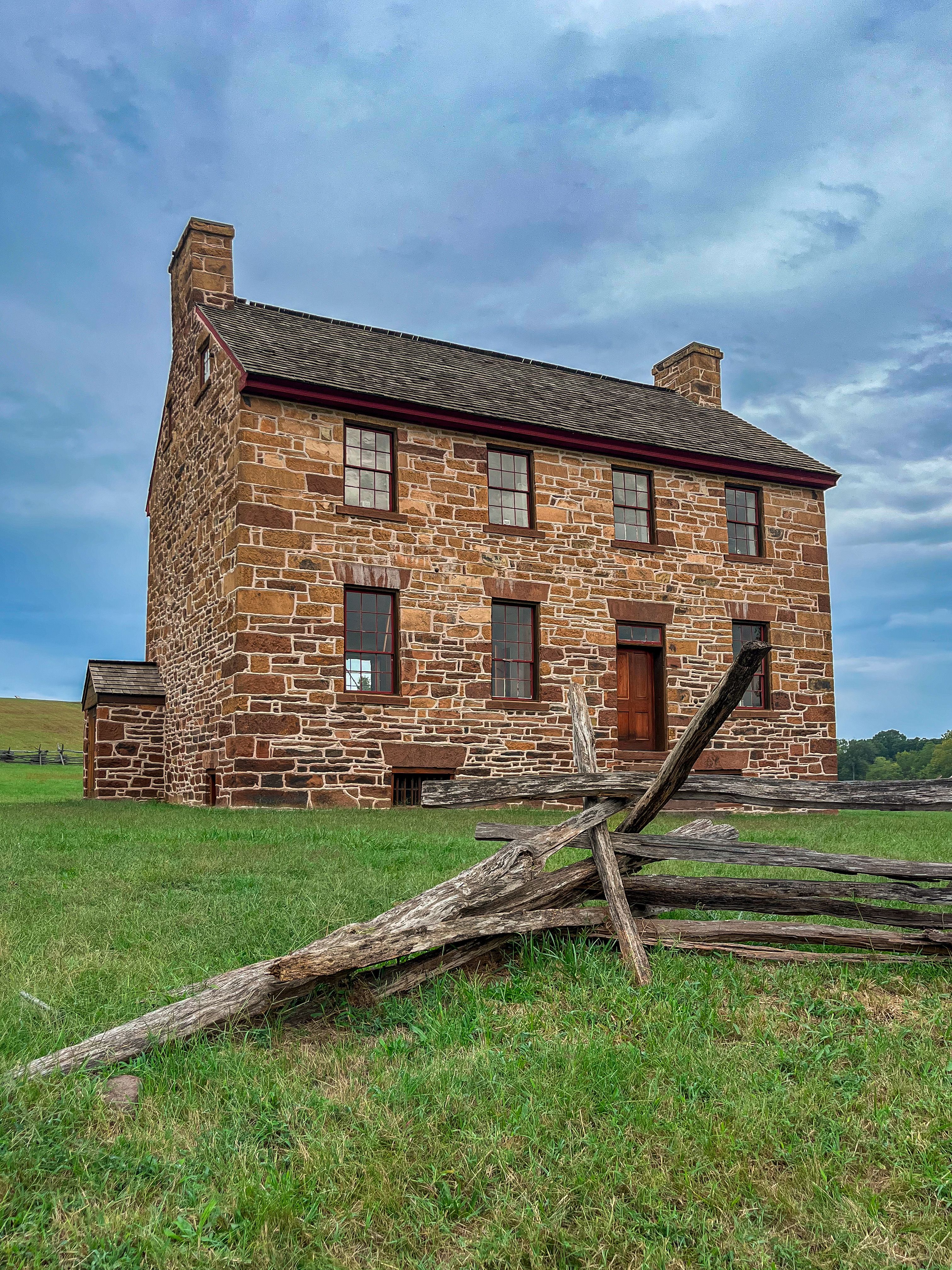Historic Red Stone House with Wooden Fence Outdoors · Free Stock Photo