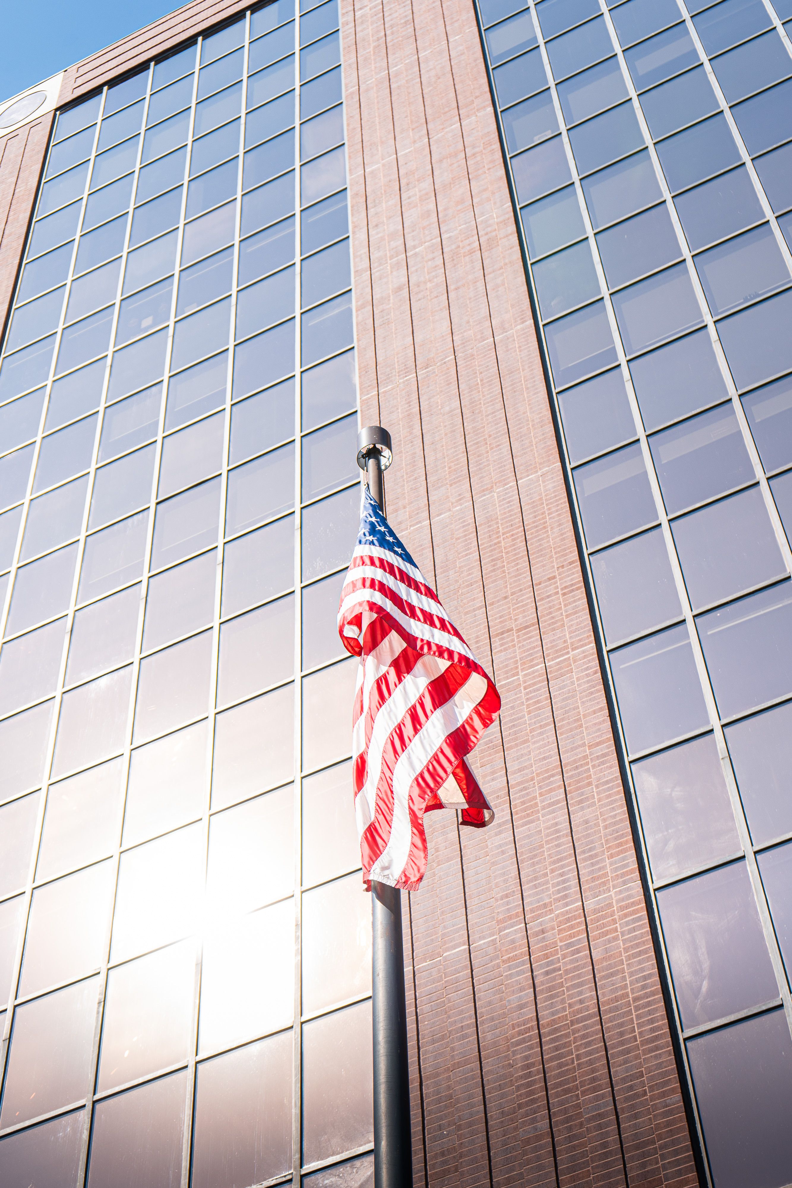 American Flag with Modern Glass Building Backdrop · Free Stock Photo