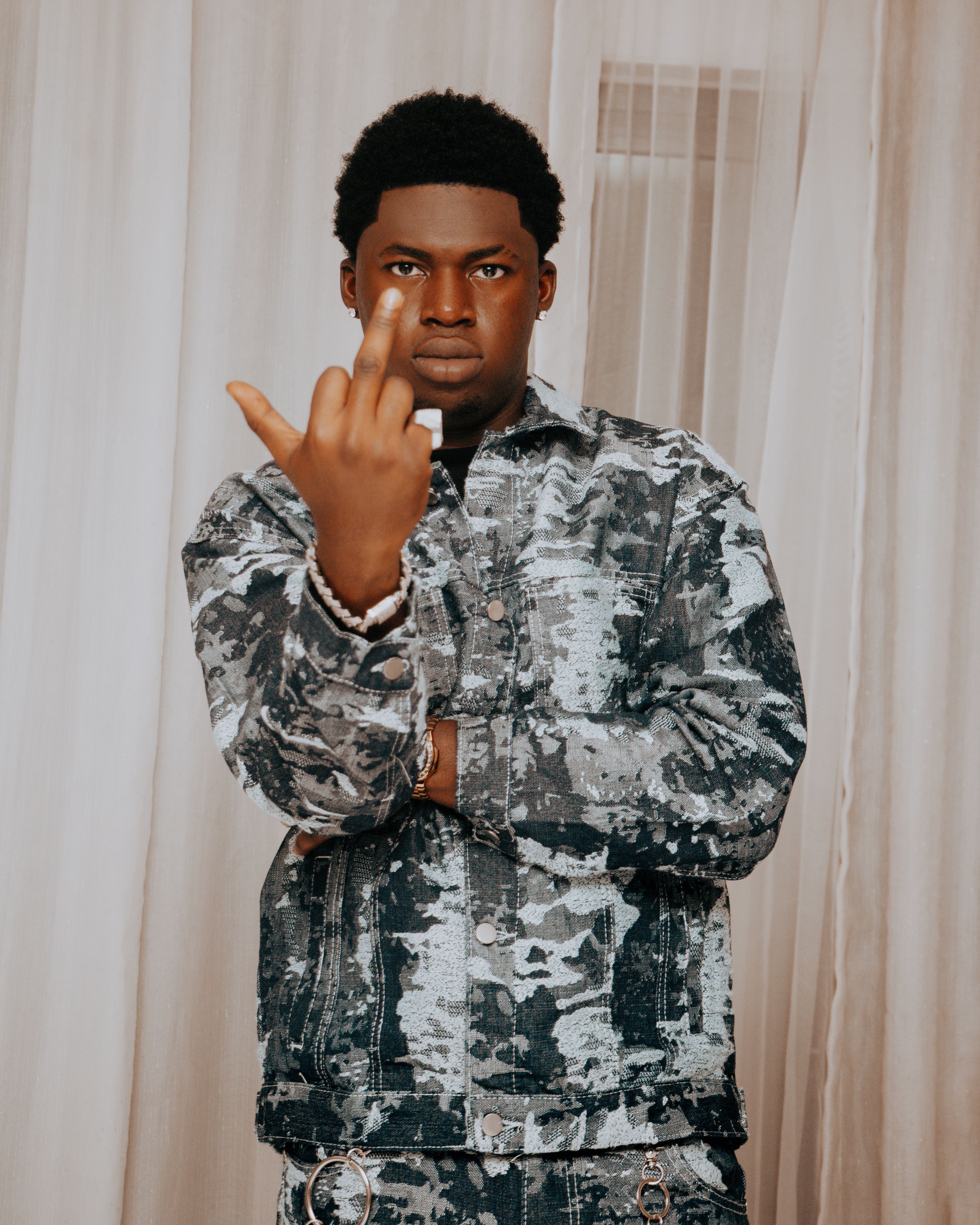 Person in Camo Jacket Showing Gesture Indoors · Free Stock Photo