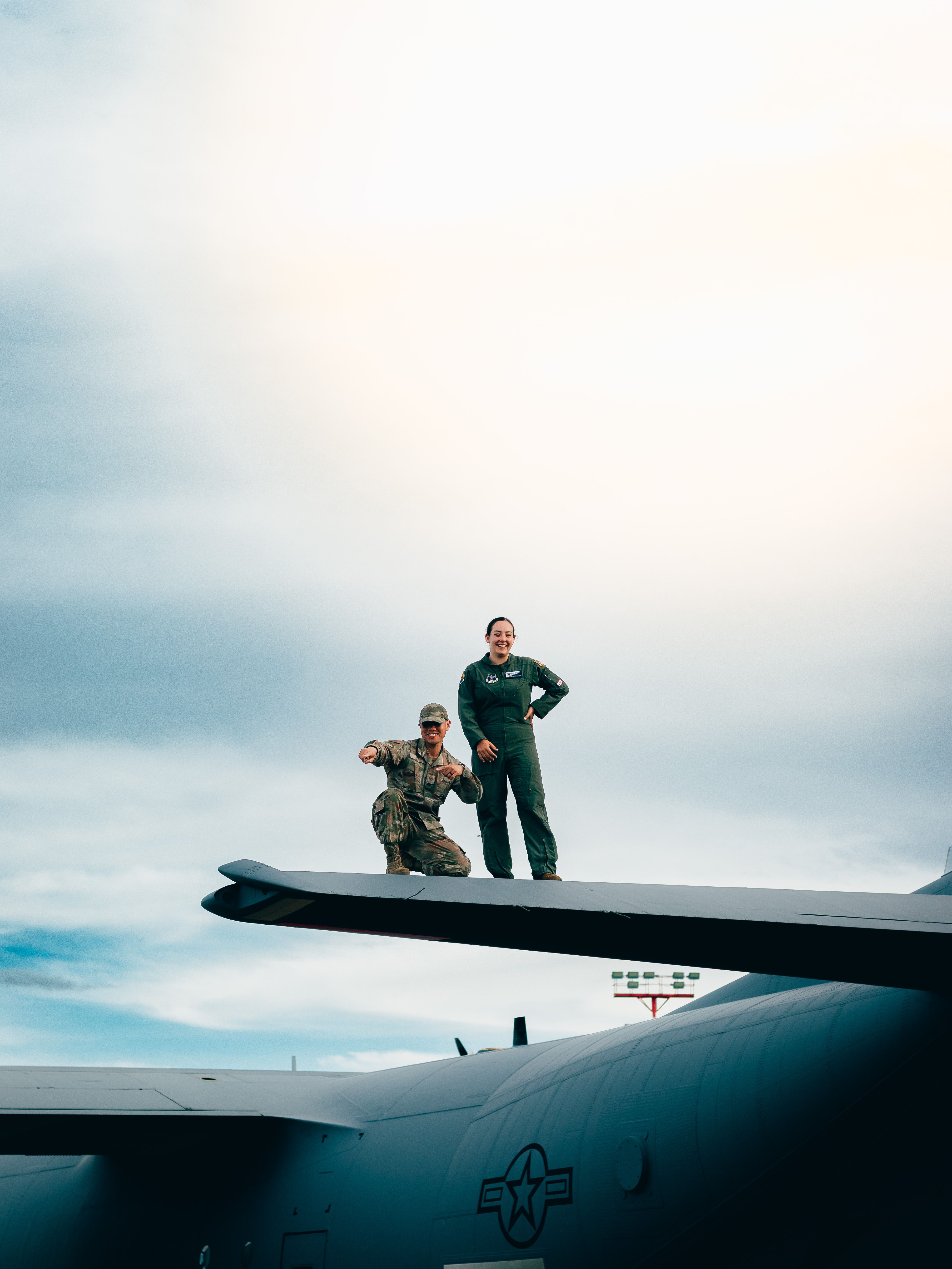 Military Personnel on Aircraft Wing Under Cloudy Sky · Free Stock Photo