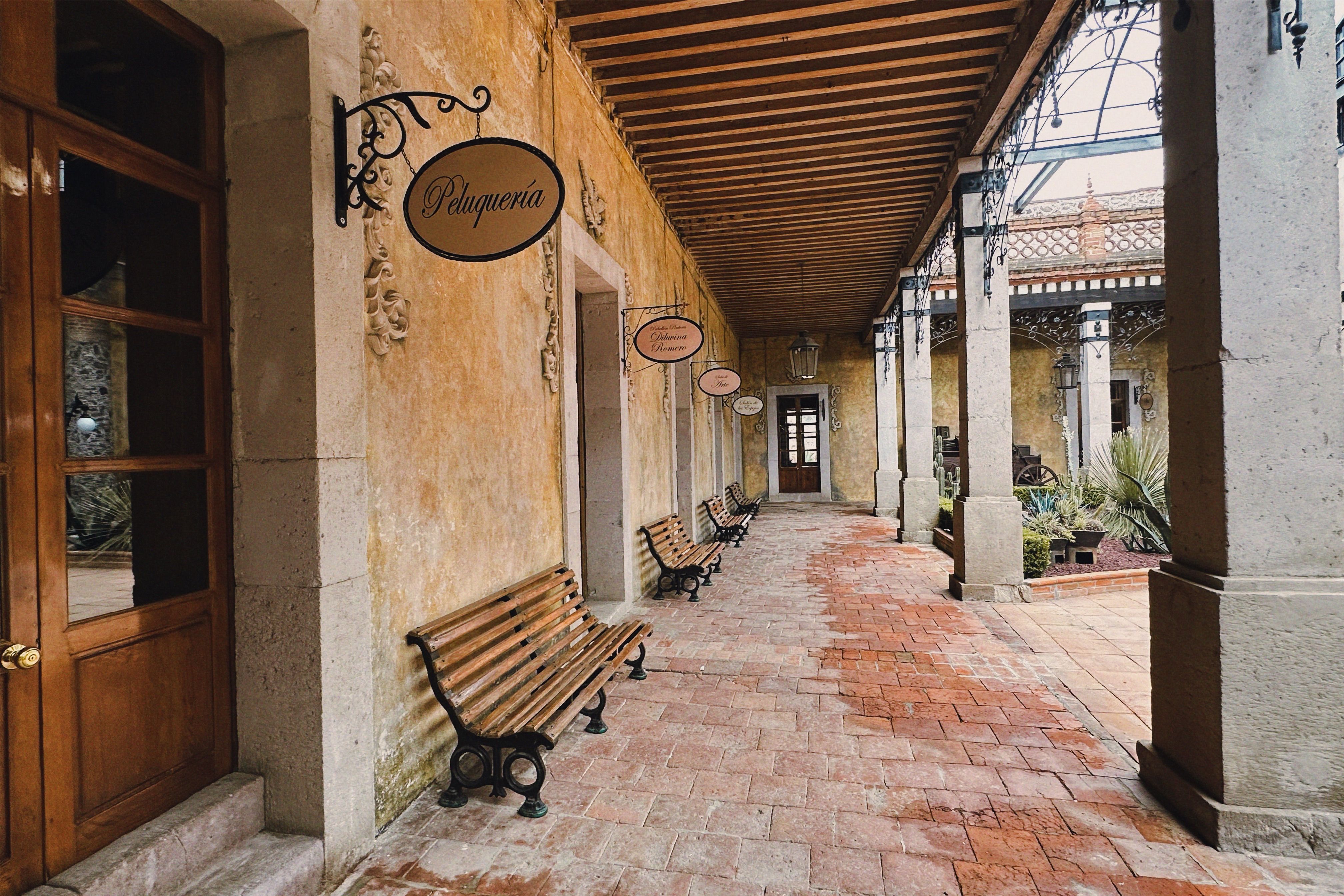 Charming Colonial Corridor with Rustic Benches · Free Stock Photo