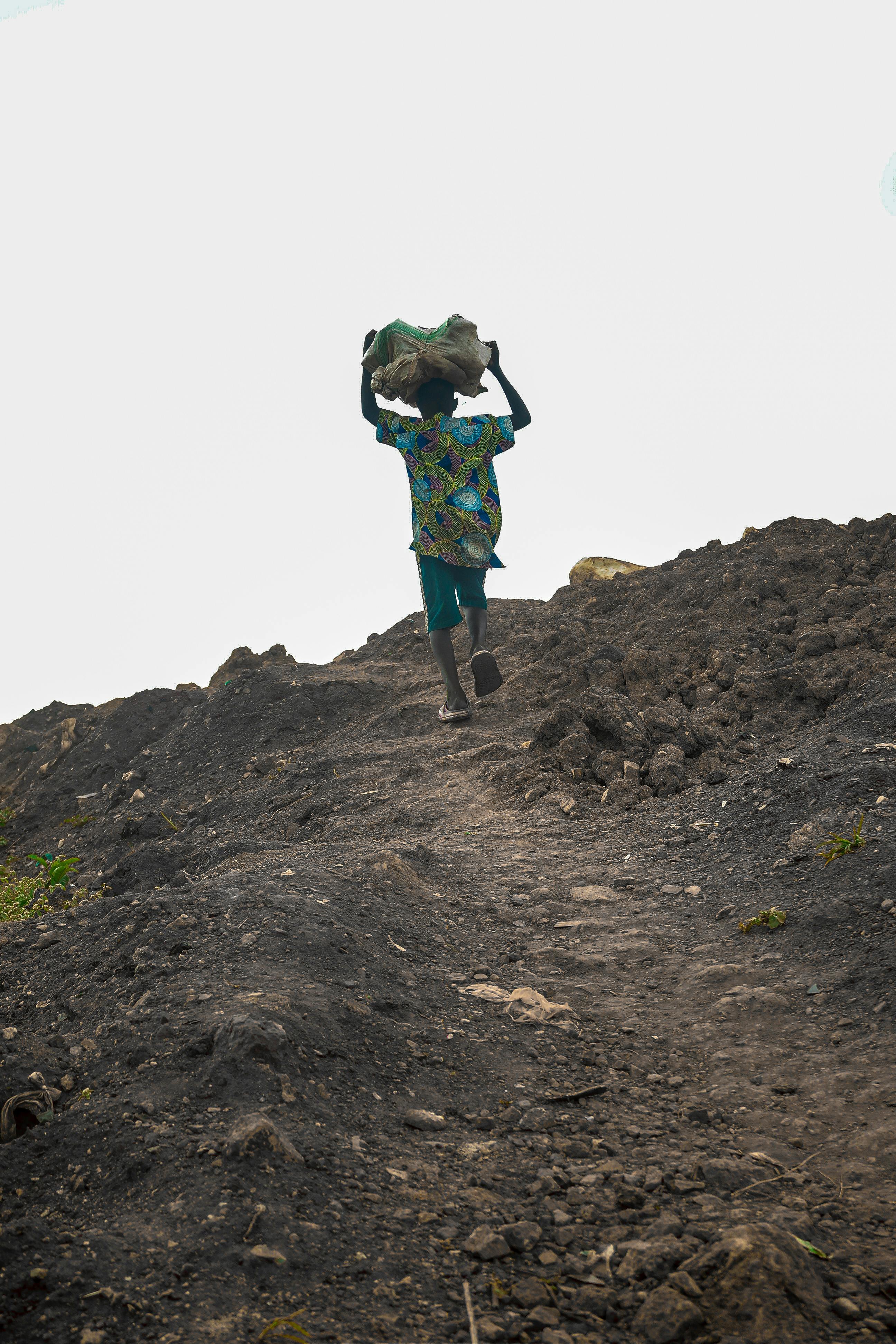 Child Carrying Load on Rocky Path in Rural Setting · Free Stock Photo