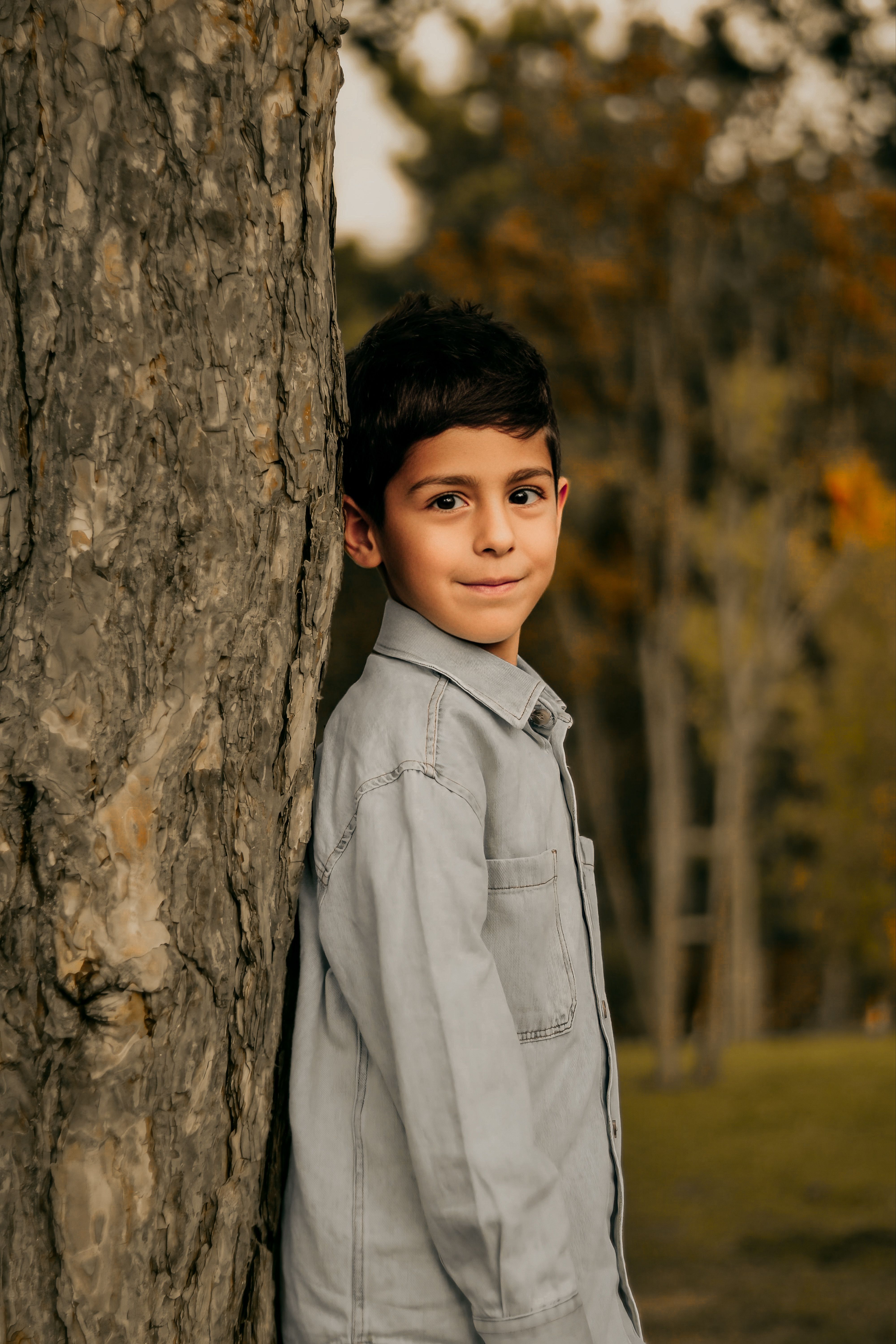 Portrait of a Young Boy Leaning Against Tree · Free Stock Photo
