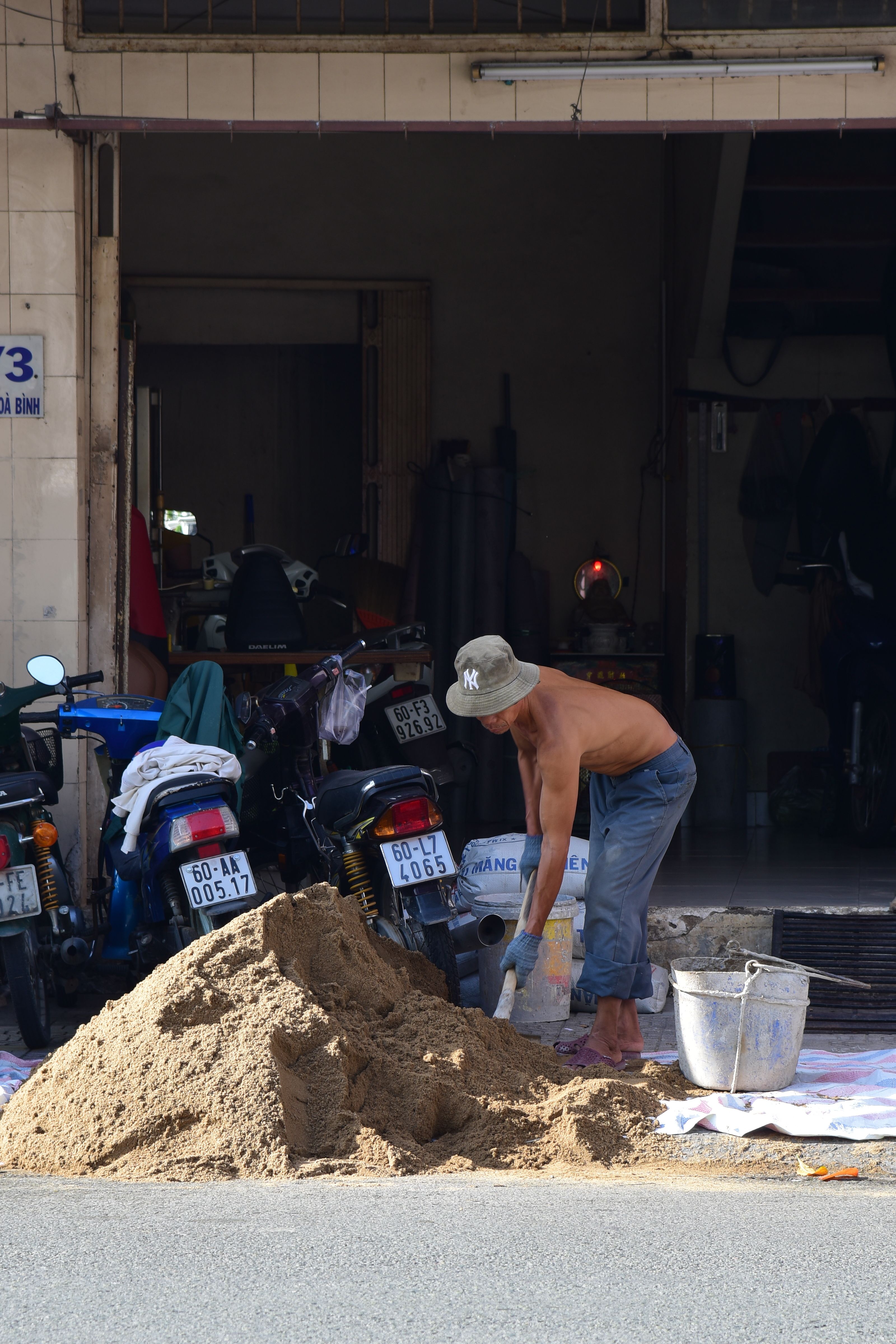 Man Working with Sand Outside Motorcycle Shop · Free Stock Photo