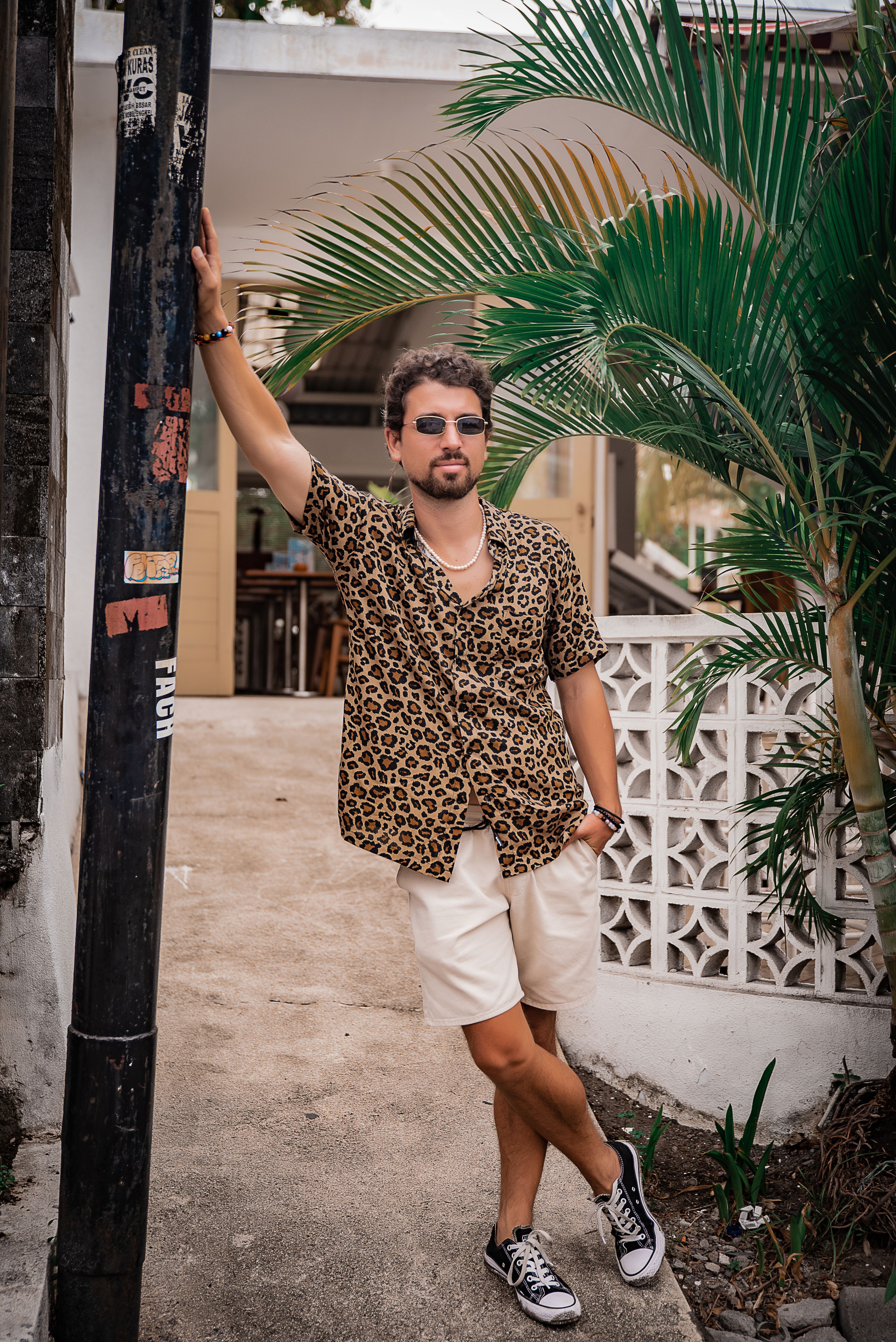 Man in Leopard Print Shirt Leaning Against Pole · Free Stock Photo