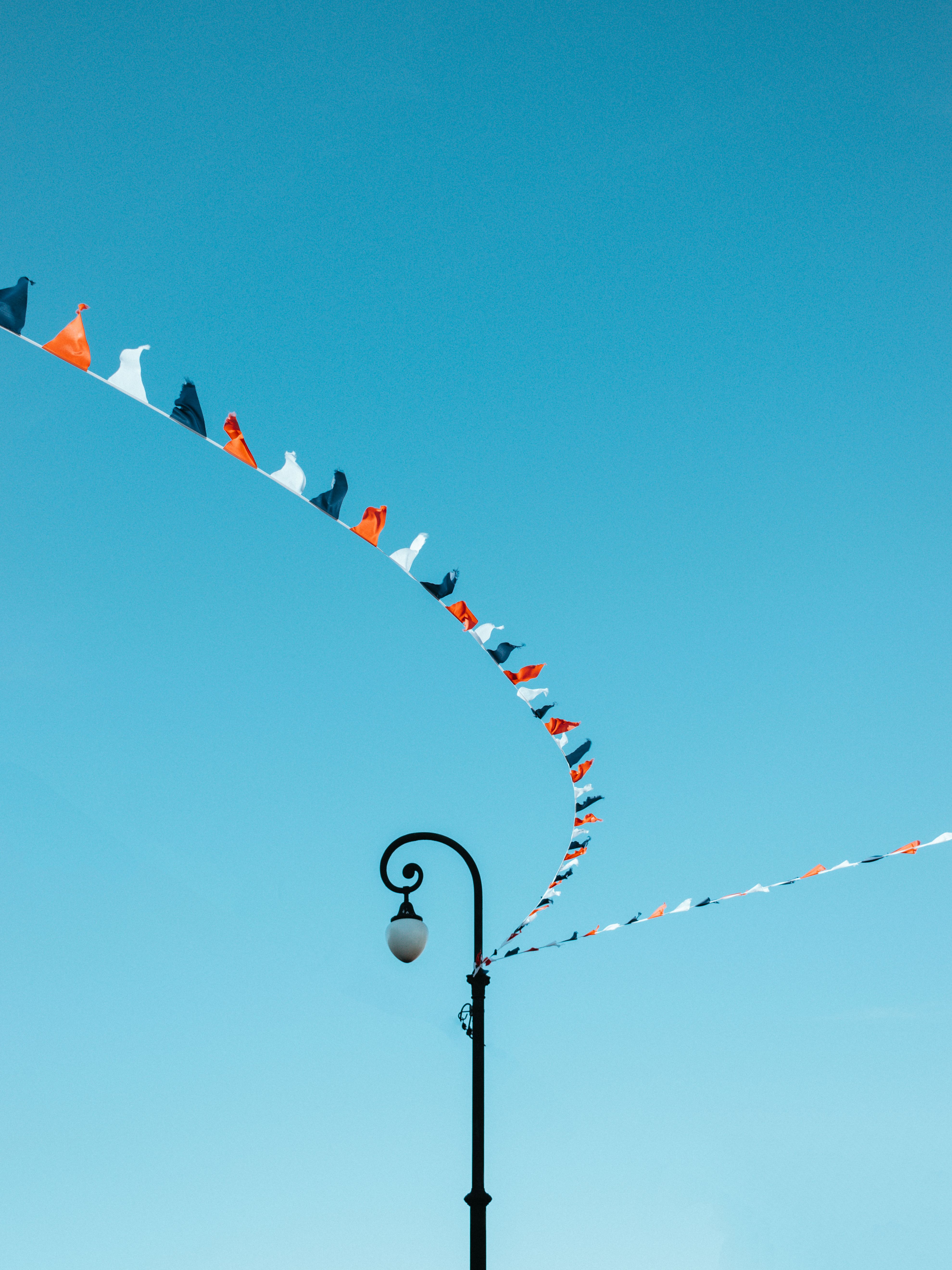 Vibrant Pennant Flags Against Clear Blue Sky · Free Stock Photo