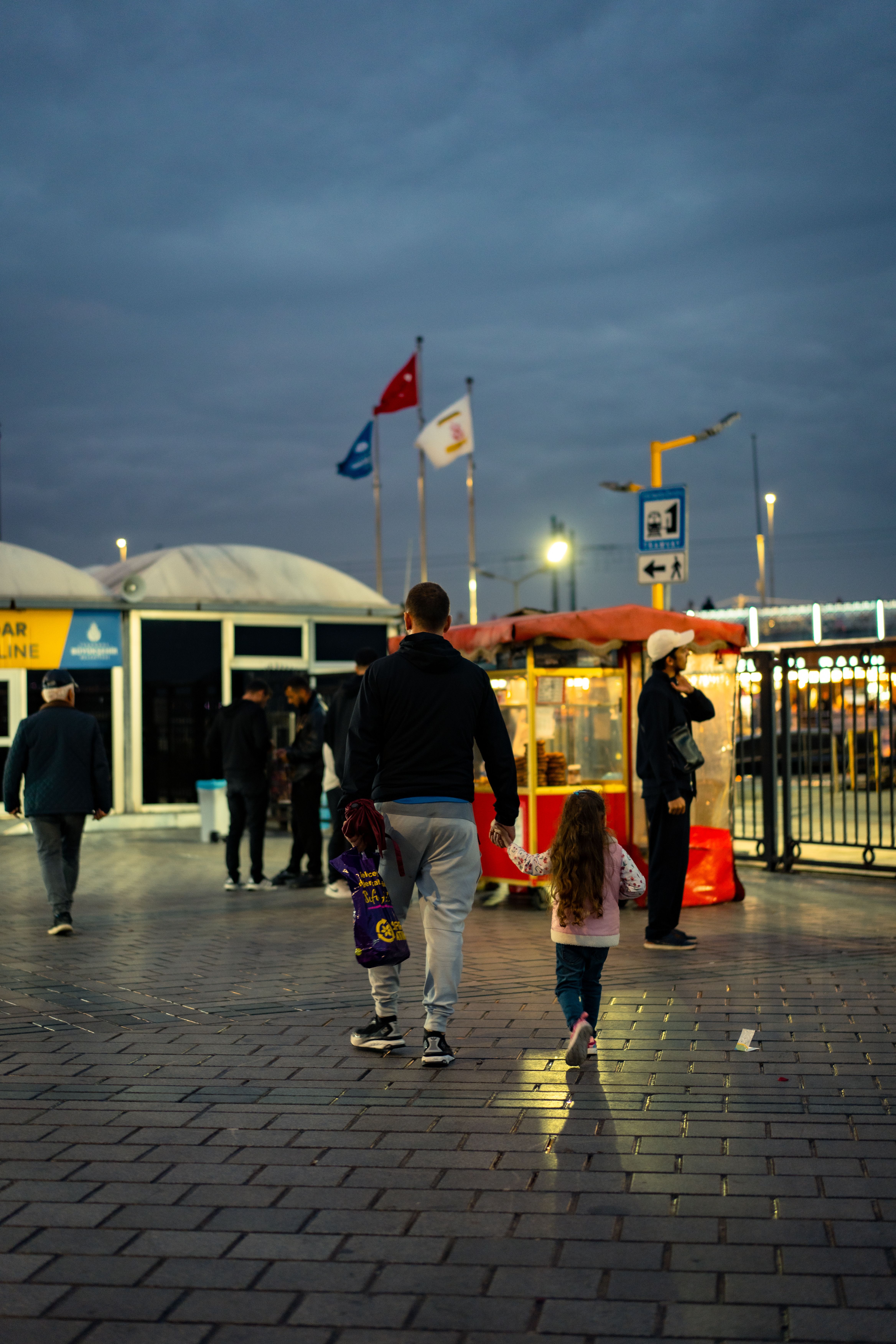 Family Evening Stroll Near Waterfront Flags · Free Stock Photo