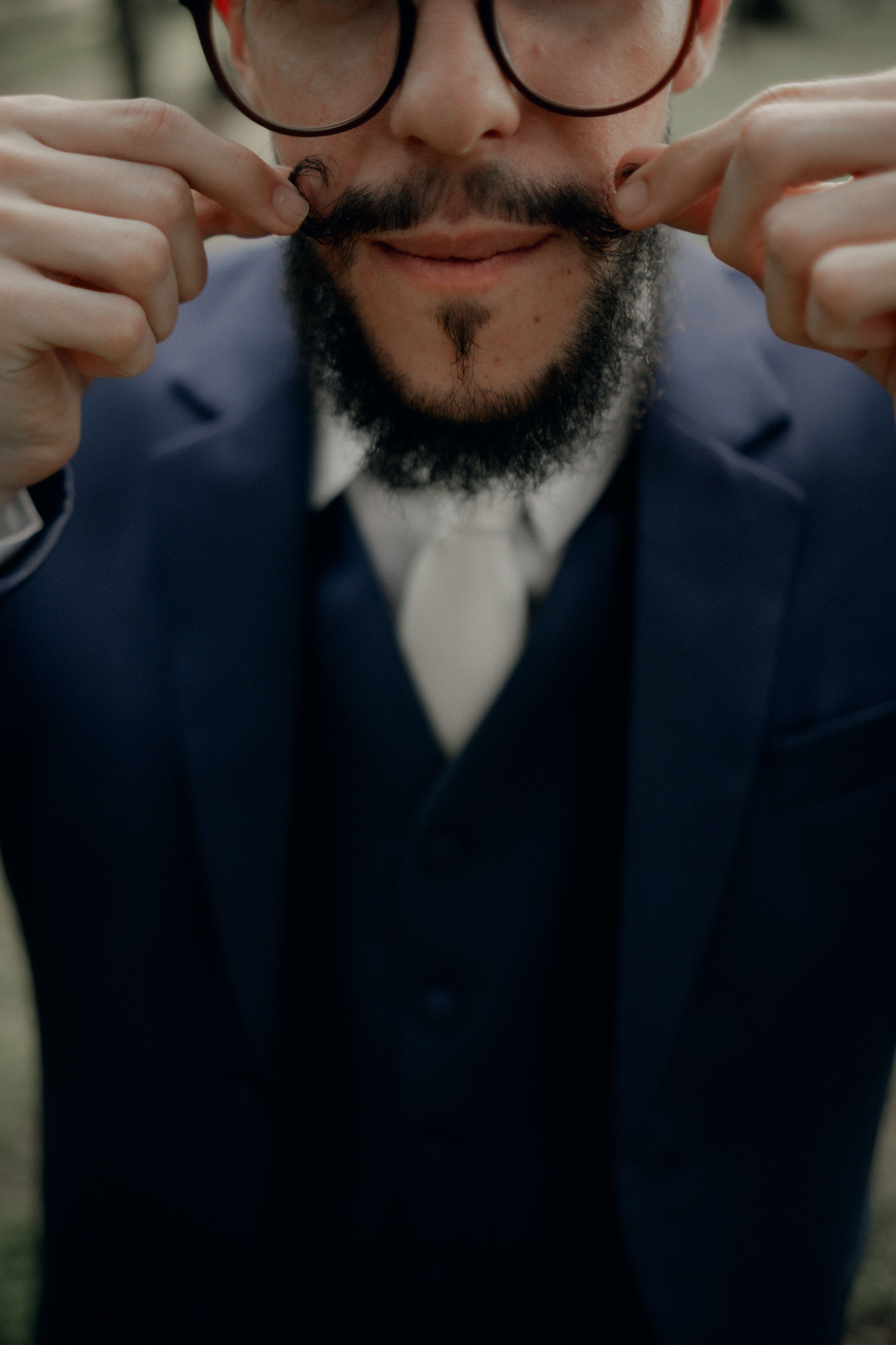 Man Adjusting Curly Mustache in Blue Suit Outdoors · Free Stock Photo