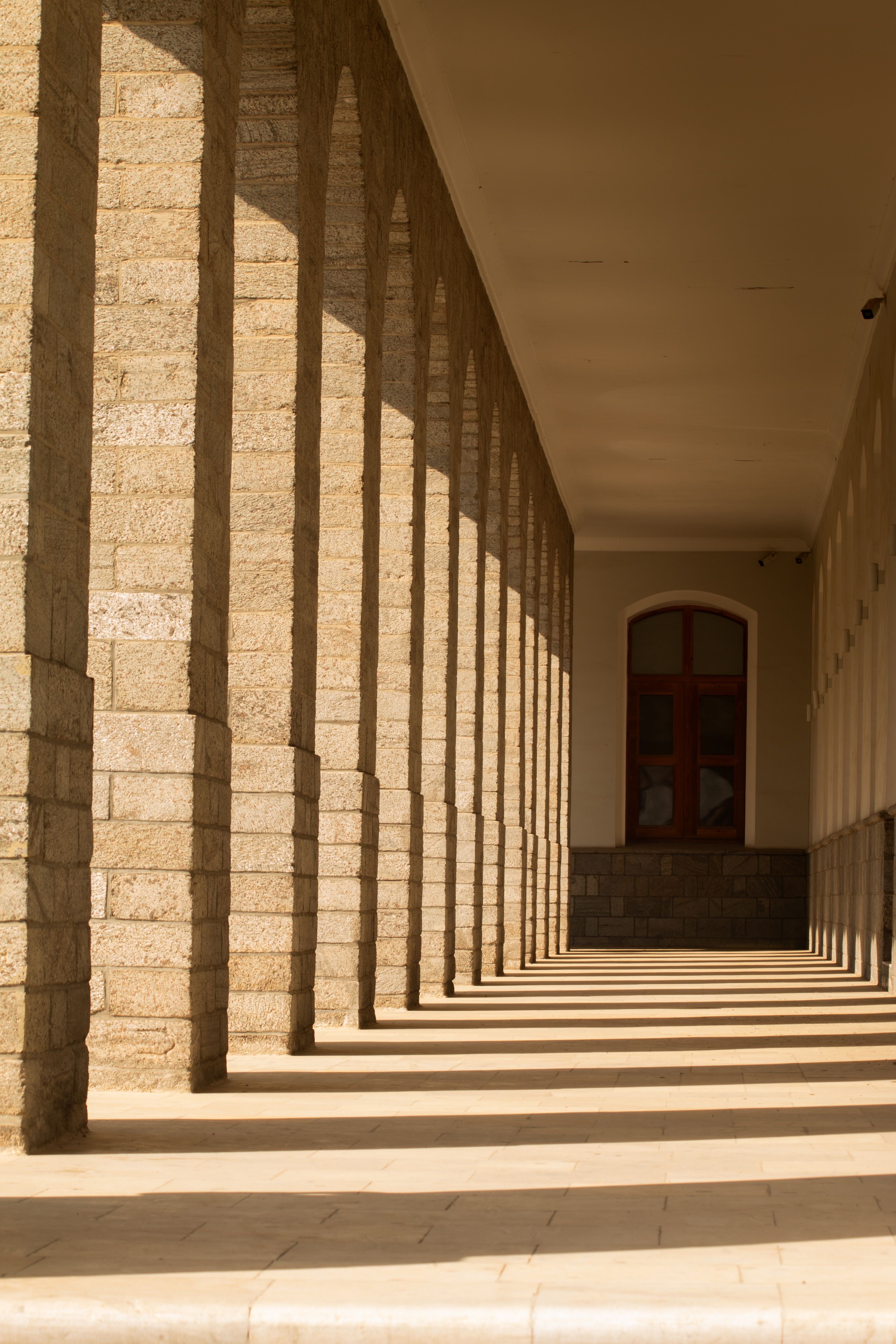 Sunlit Stone Corridor with Architectural Arches · Free Stock Photo