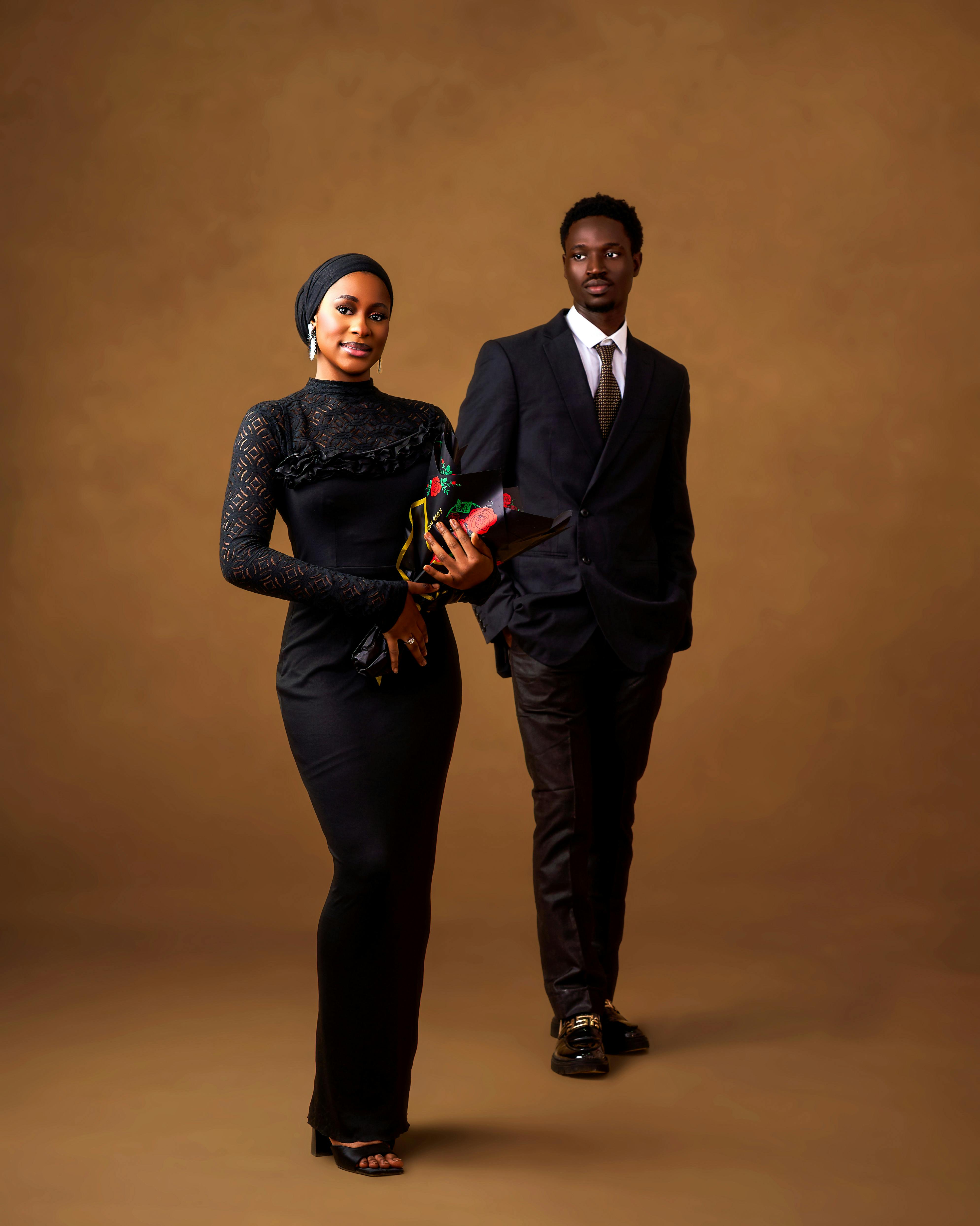 Elegant Couple in Formal Attire Against Brown Backdrop · Free Stock Photo