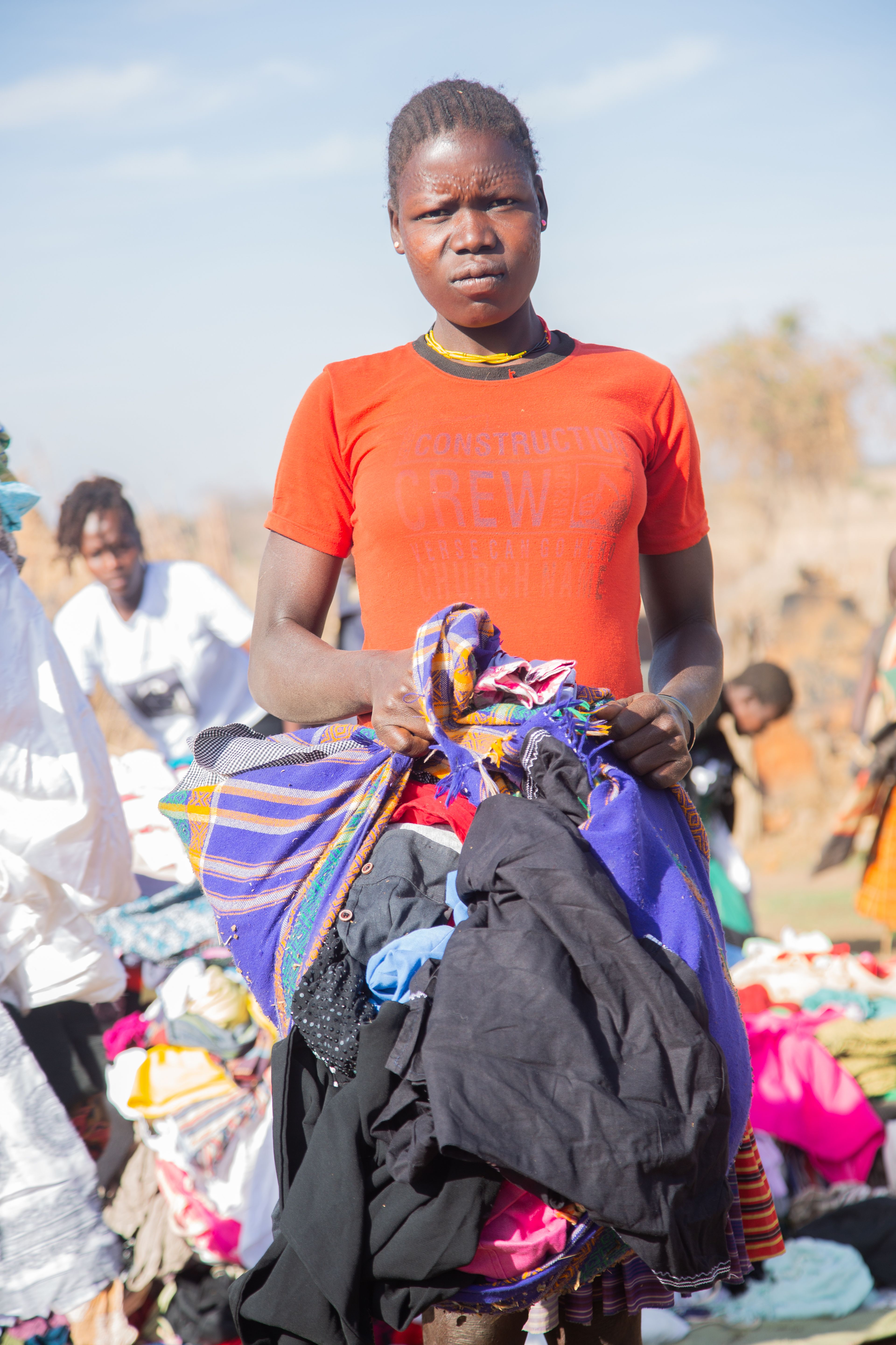Young Woman Sorting Colorful Clothes Outdoors · Free Stock Photo