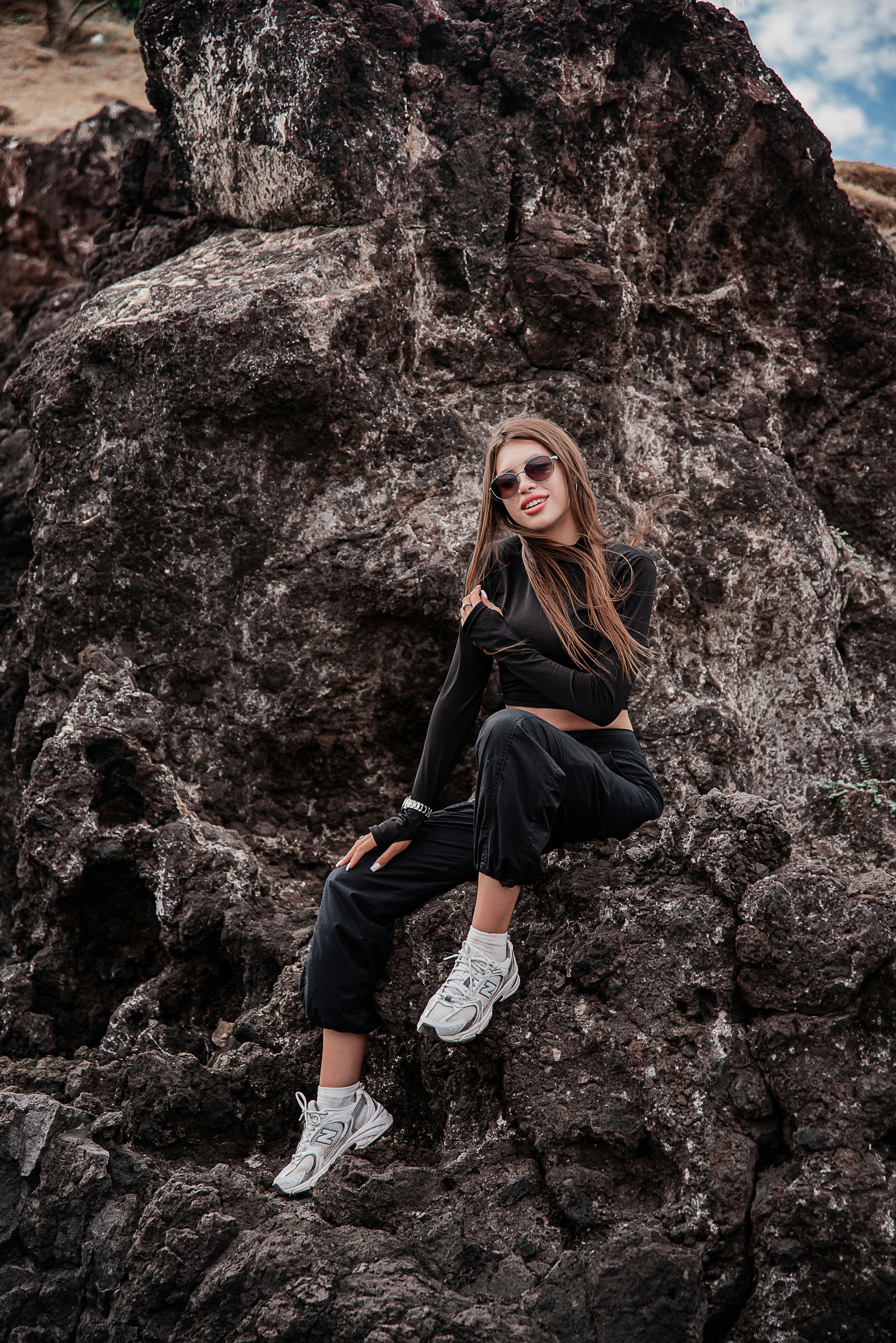 Young Woman Posing on Rocky Cliff in Sunglasses · Free Stock Photo