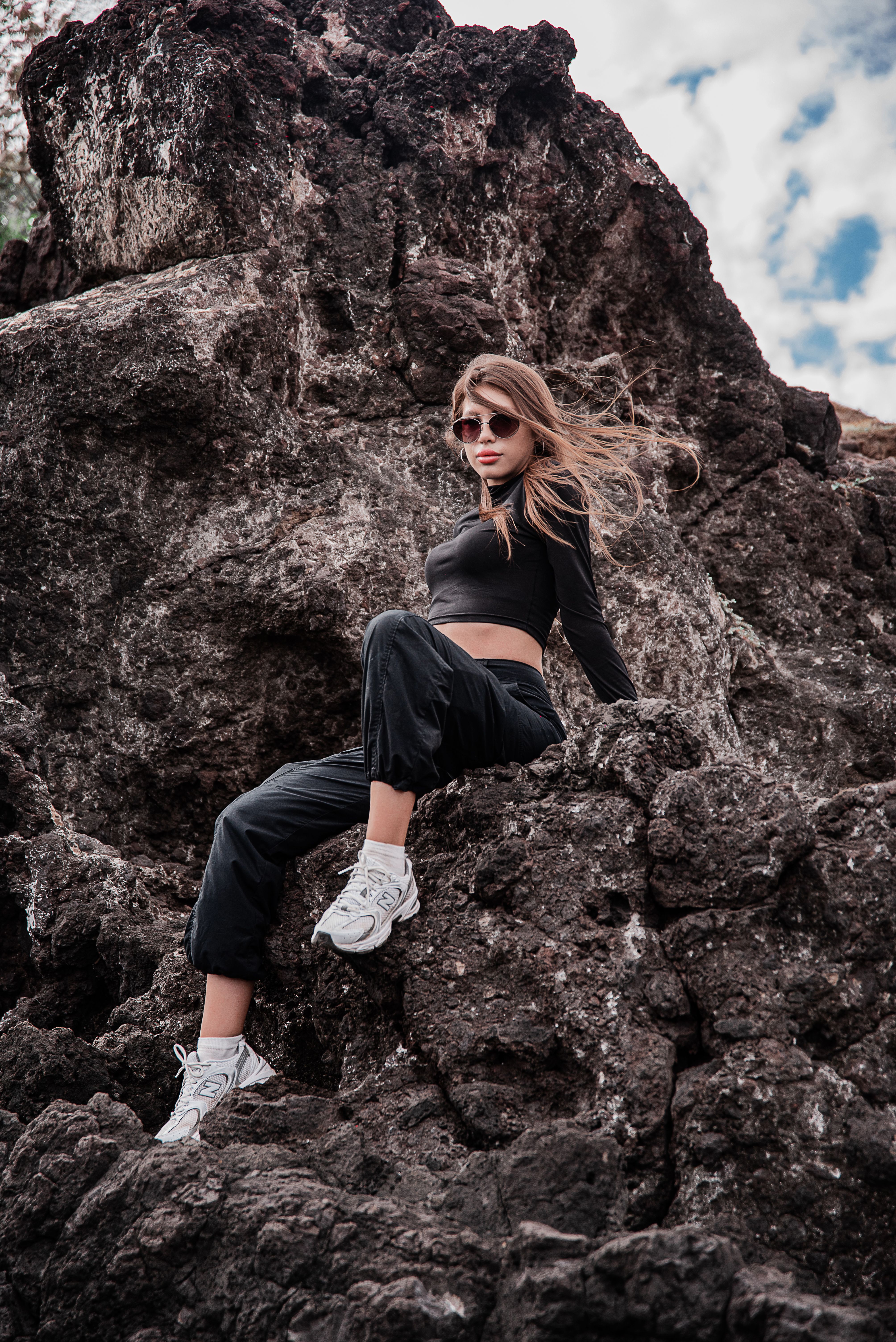 Woman in Sporty Outfit Sitting on Rocky Terrain · Free Stock Photo