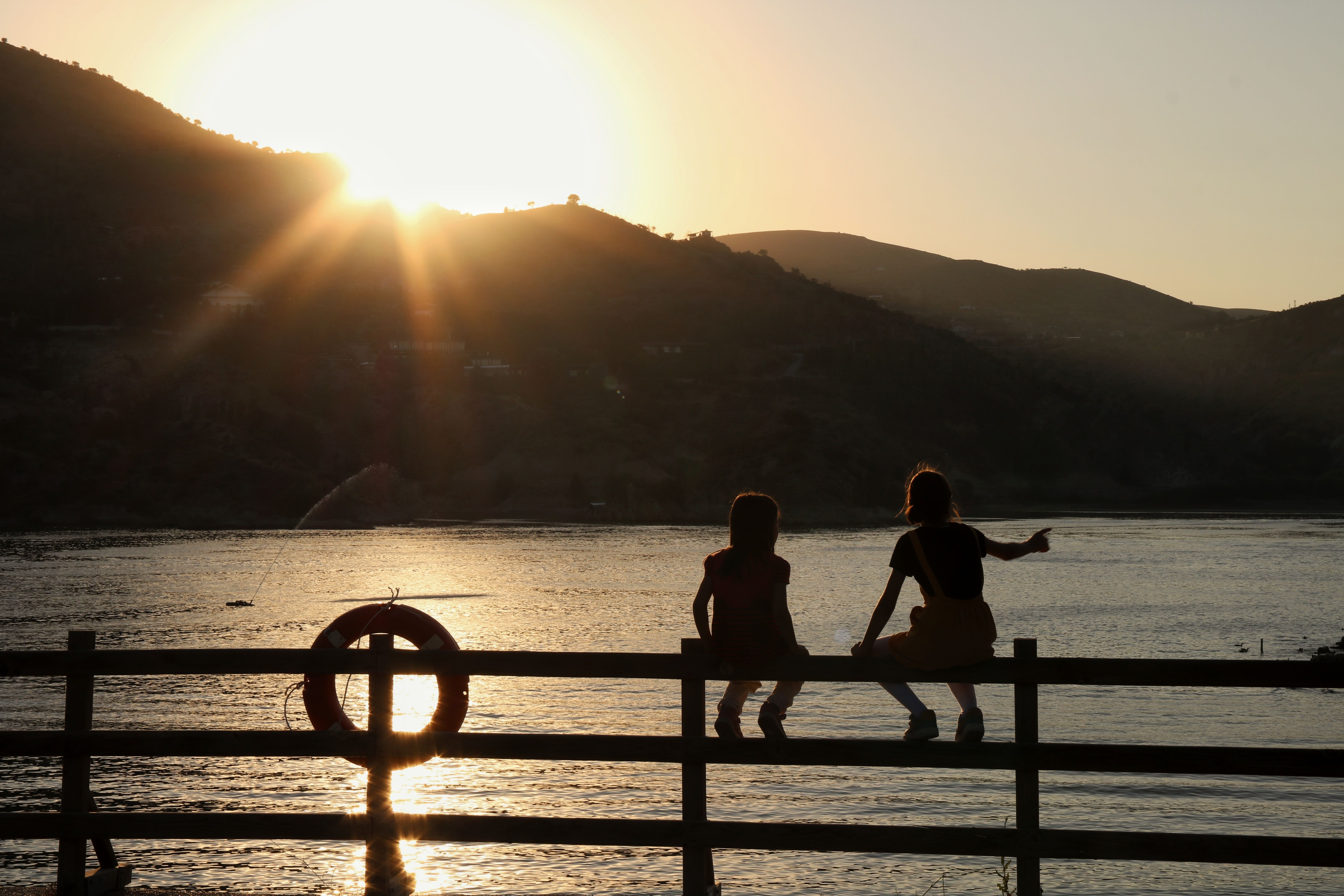 Children Watching Sunset by Lakeside Fence · Free Stock Photo