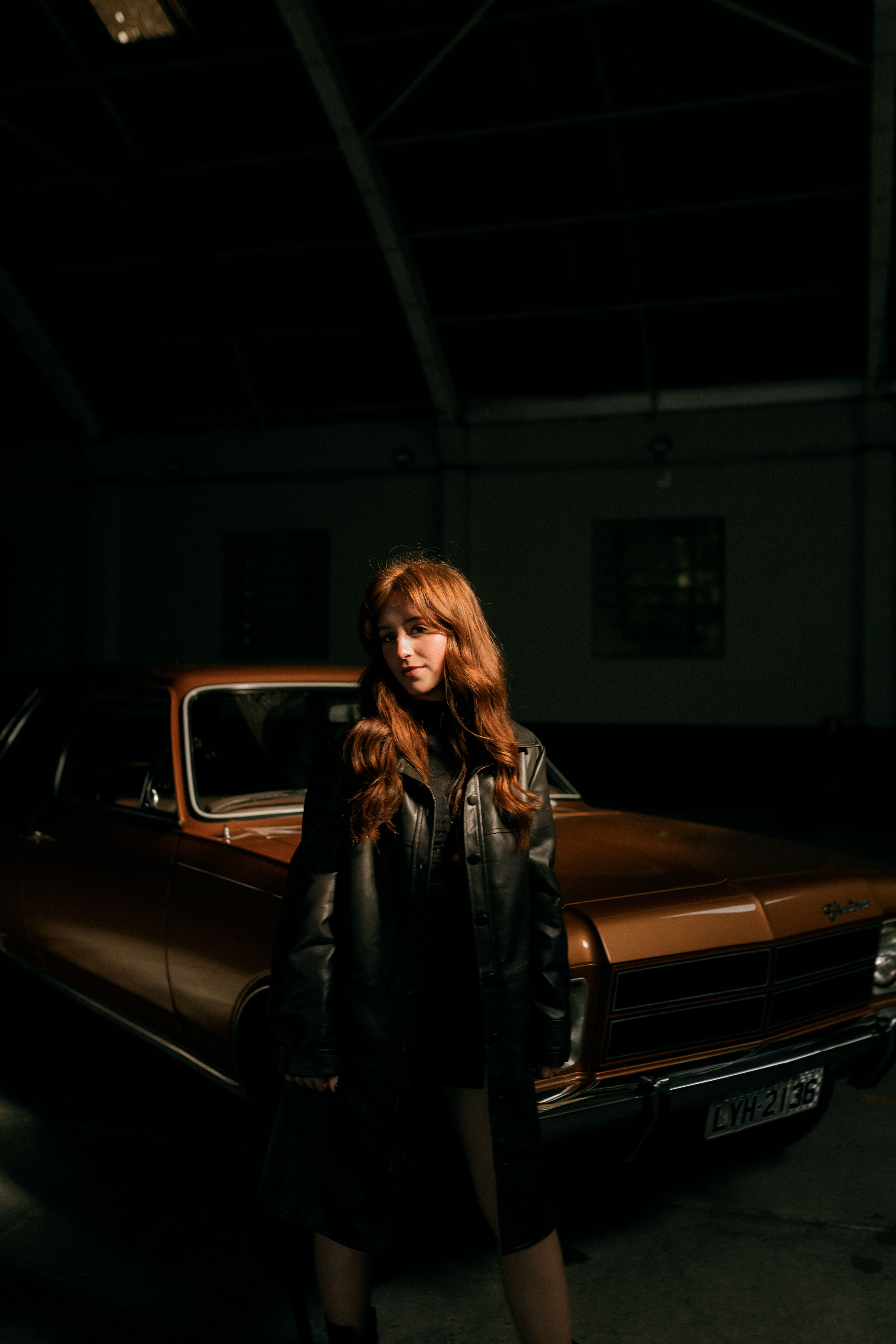 Young Woman with Classic Car in Dim Garage · Free Stock Photo