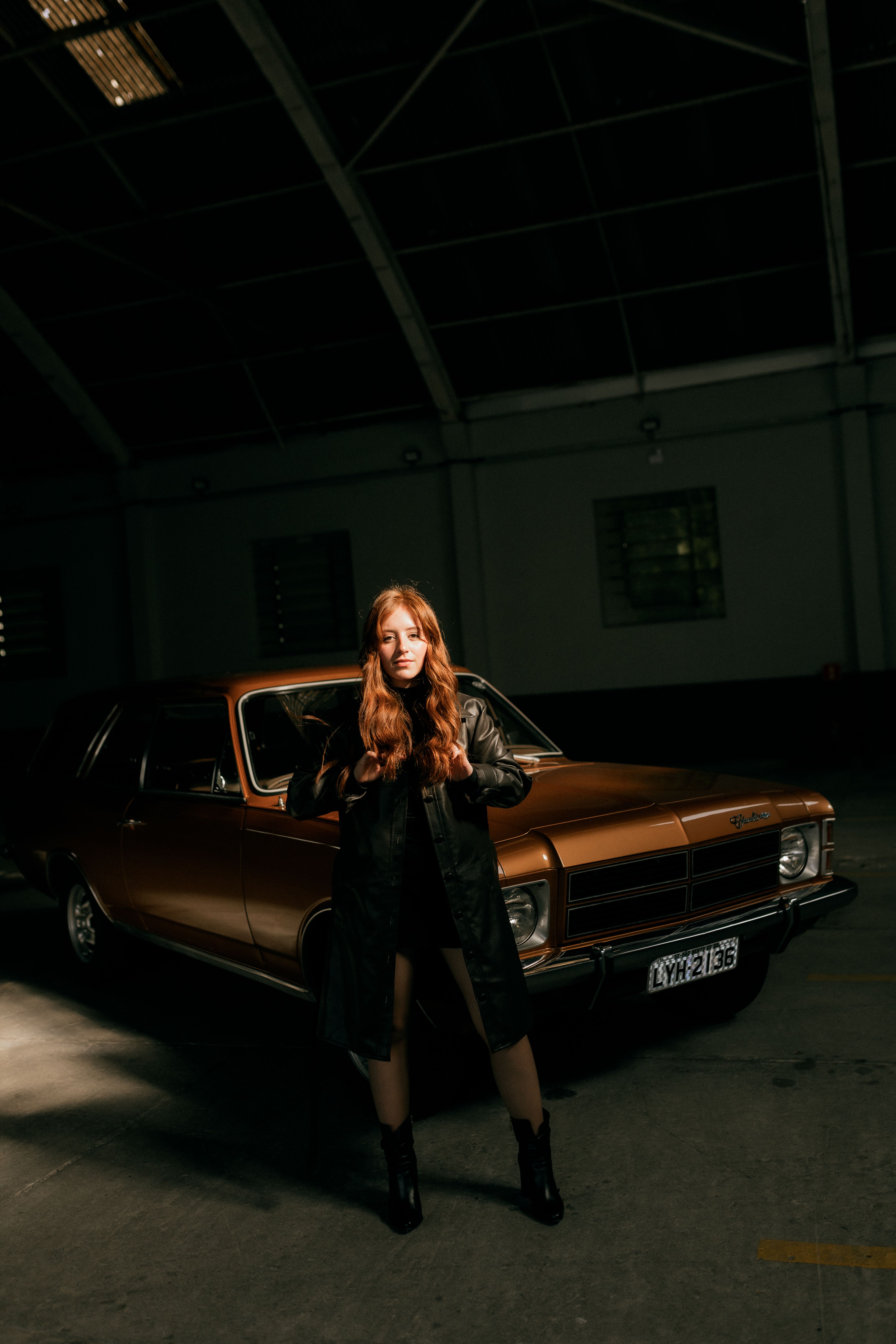 Young Woman with Classic Car in Dim Garage · Free Stock Photo