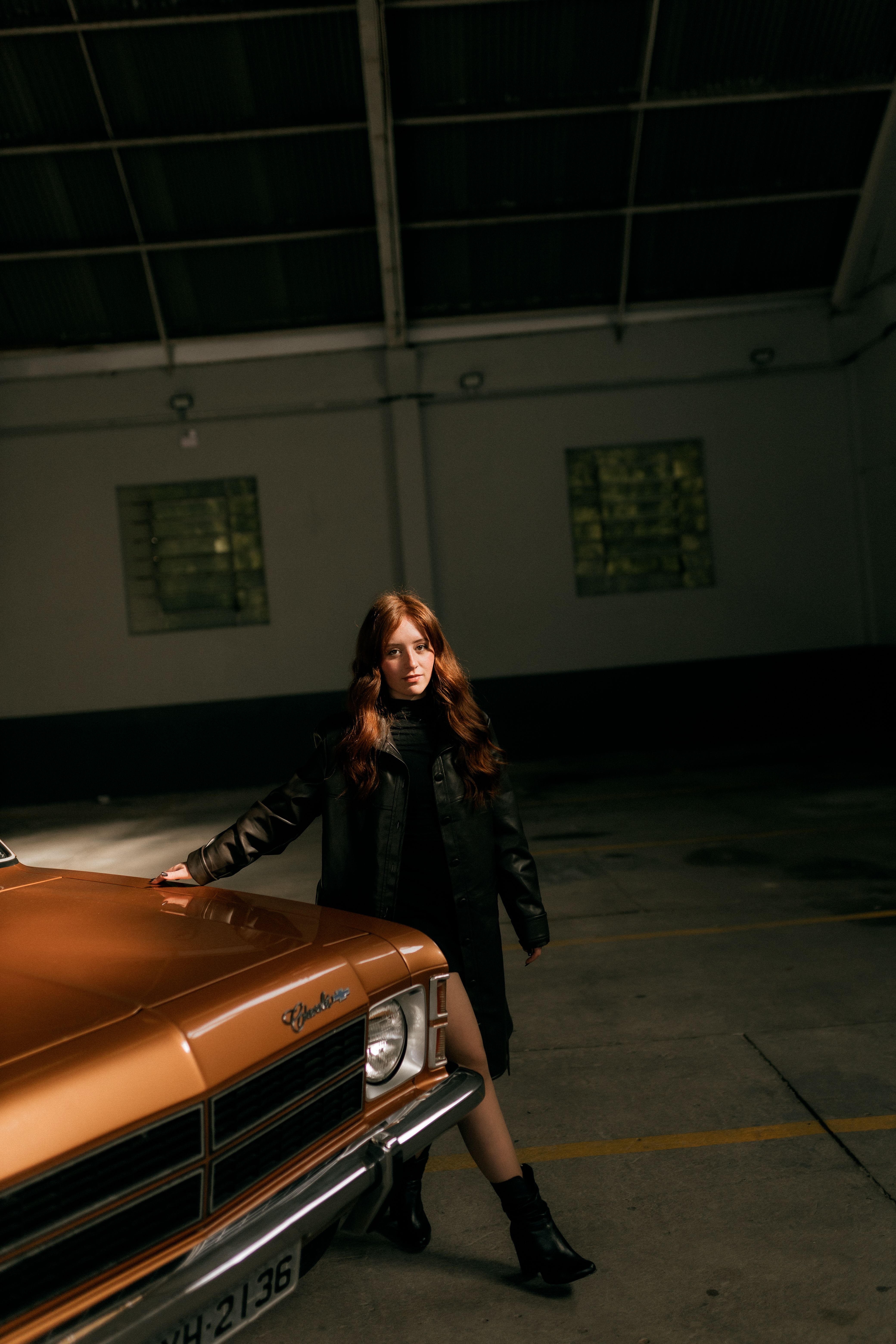 Young Woman with Classic Car in Dim Garage · Free Stock Photo