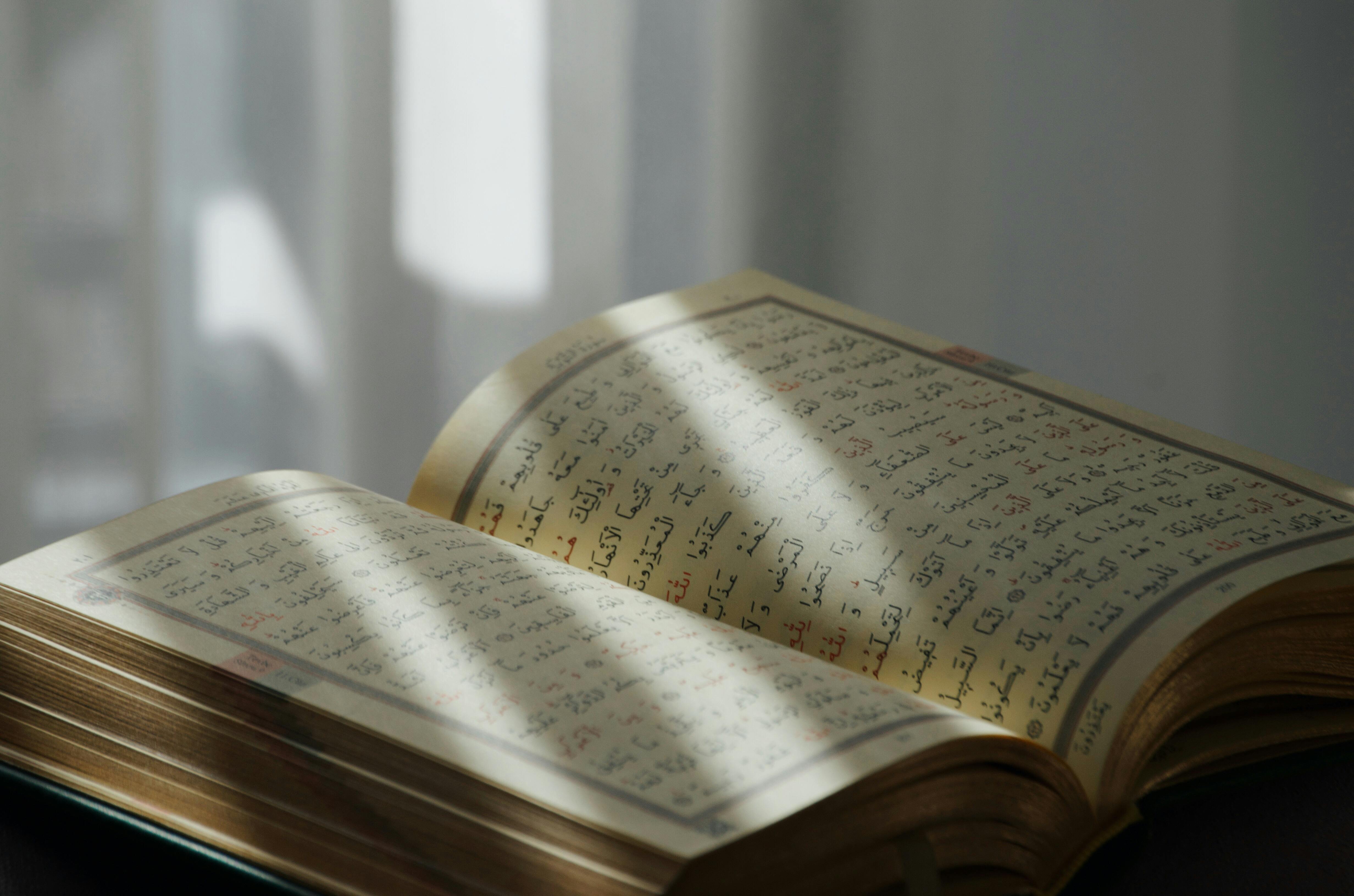 Open Quran with Sunlight Streaming Across Pages · Free Stock Photo