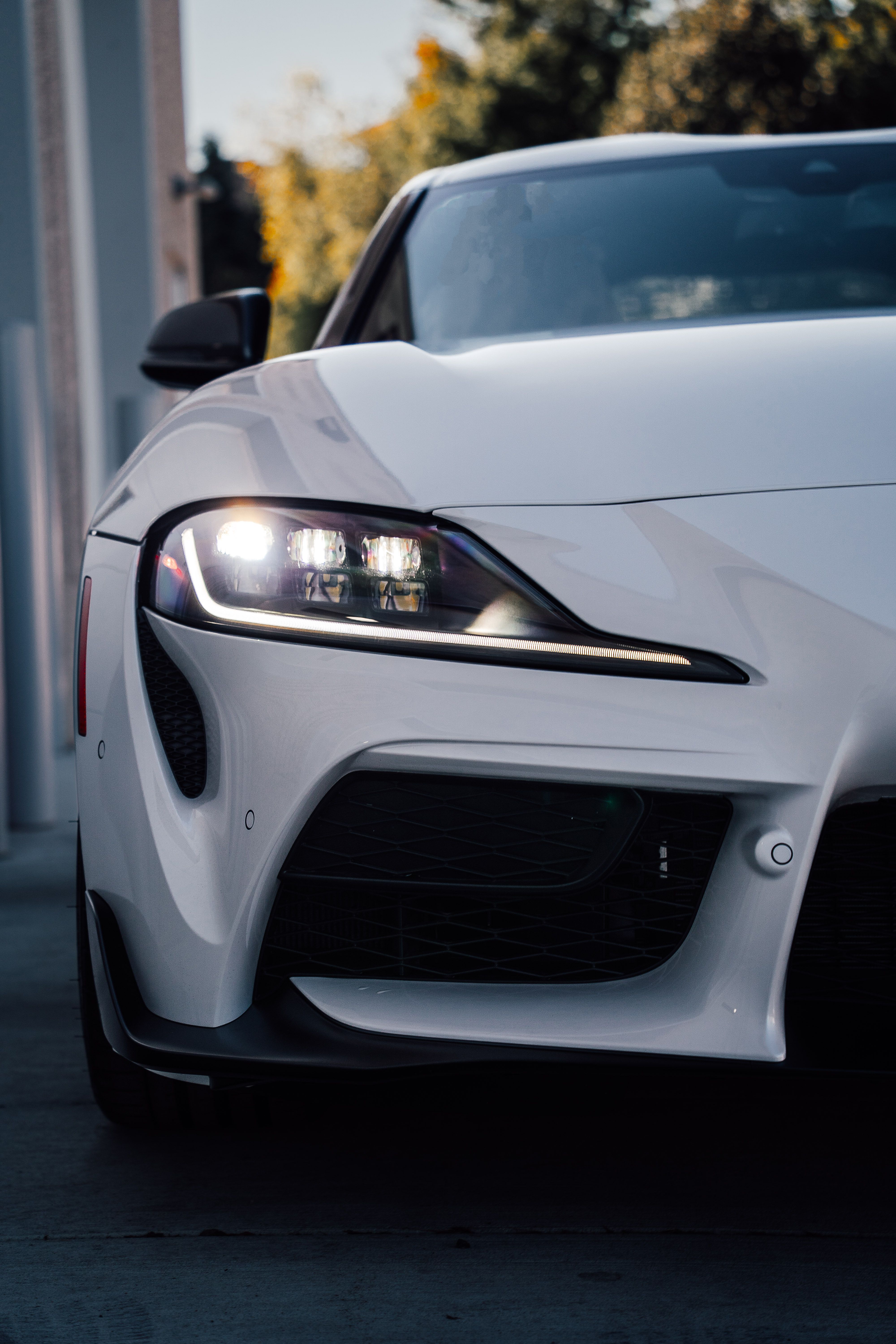Close-Up of a White Sports Car with Headlights On · Free Stock Photo