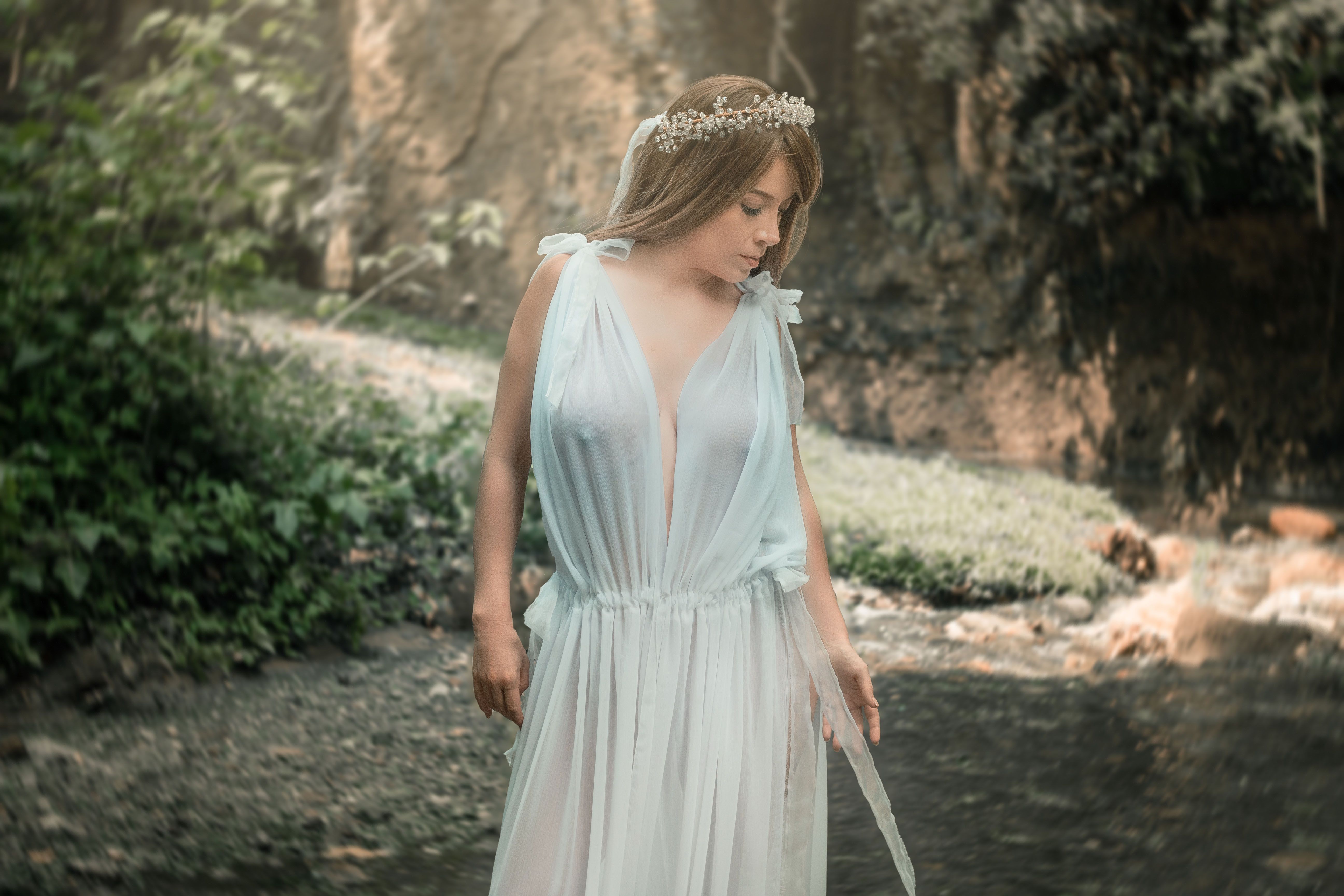Ethereal Woman in Flowing Dress by Forest Stream · Free Stock Photo