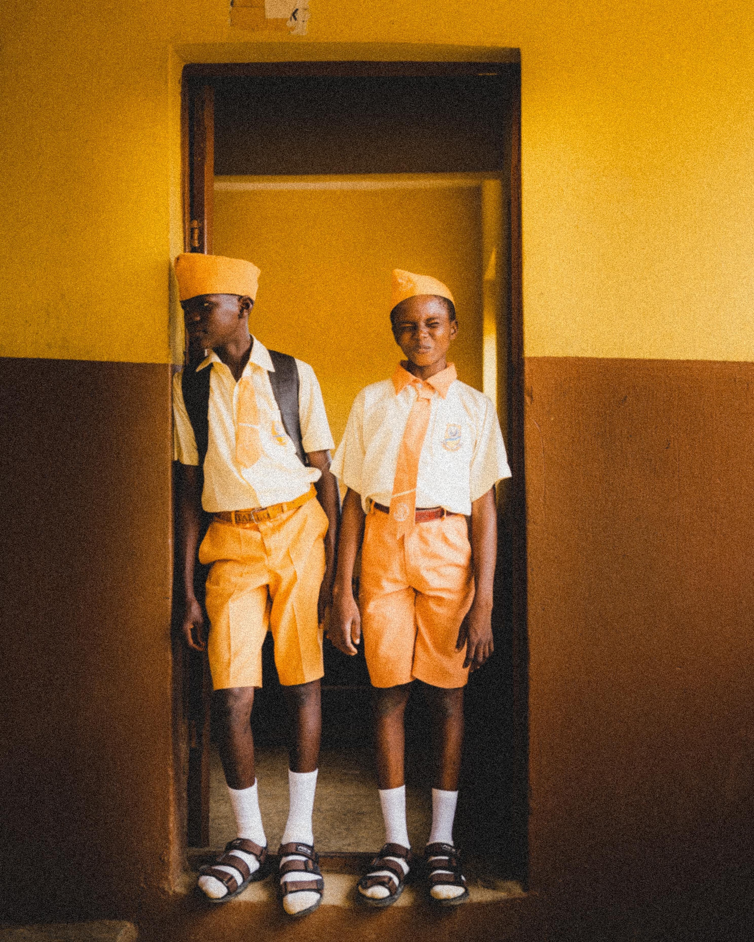 Two School Children in Uniform Standing in Doorway · Free Stock Photo