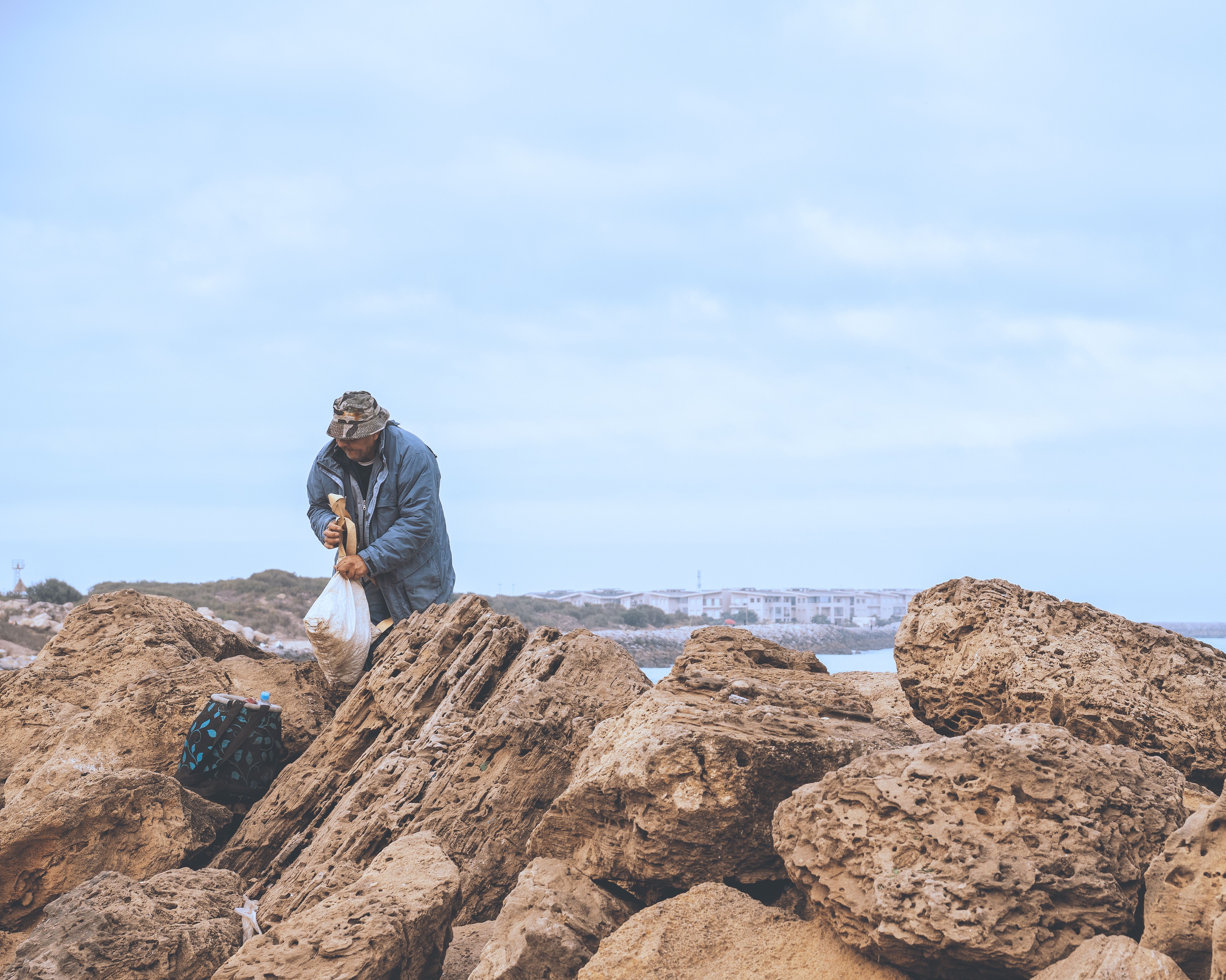 Man Collecting Items Among Coastal Rocks · Free Stock Photo