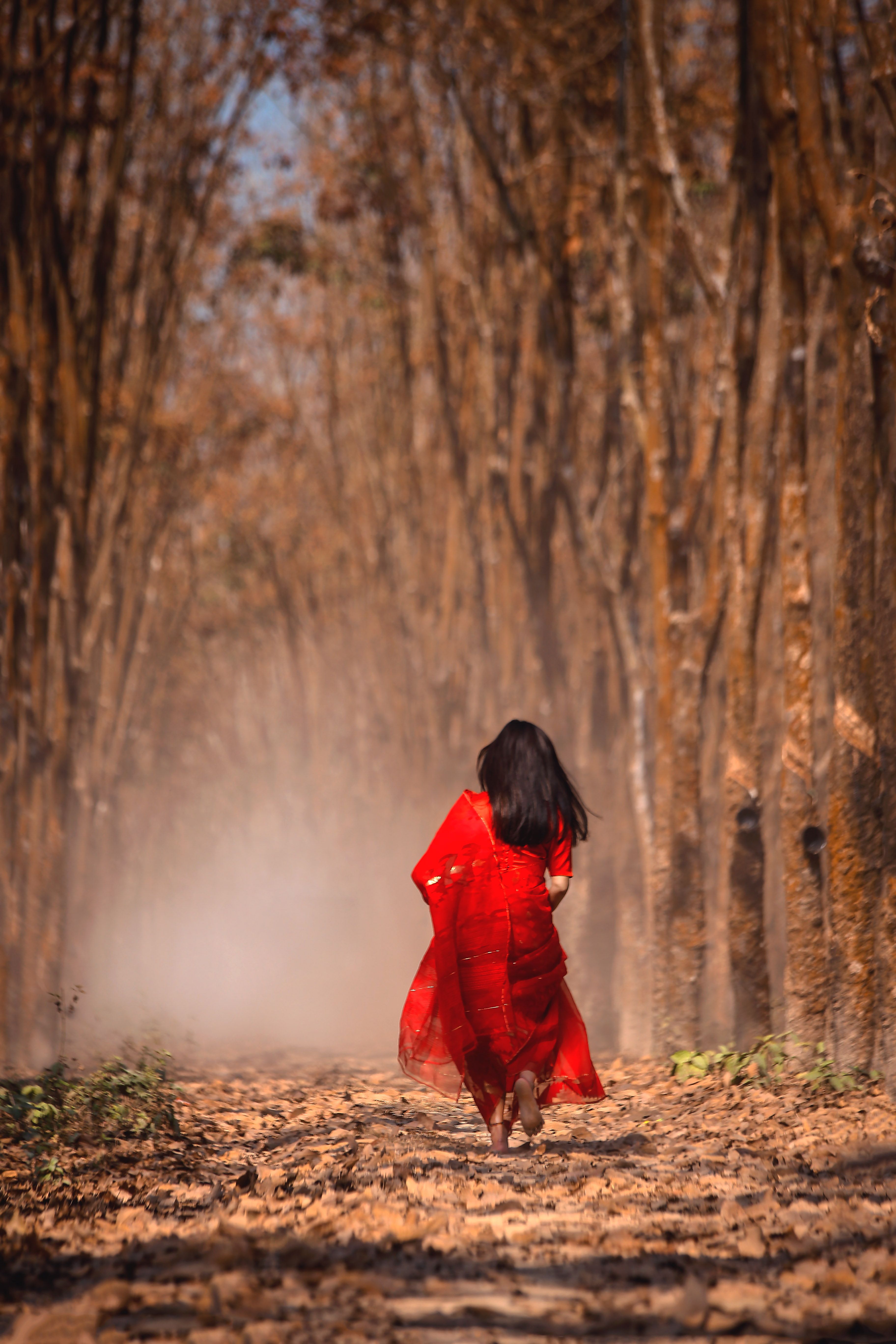Woman in Red Running Through Autumn Forest Path · Free Stock Photo