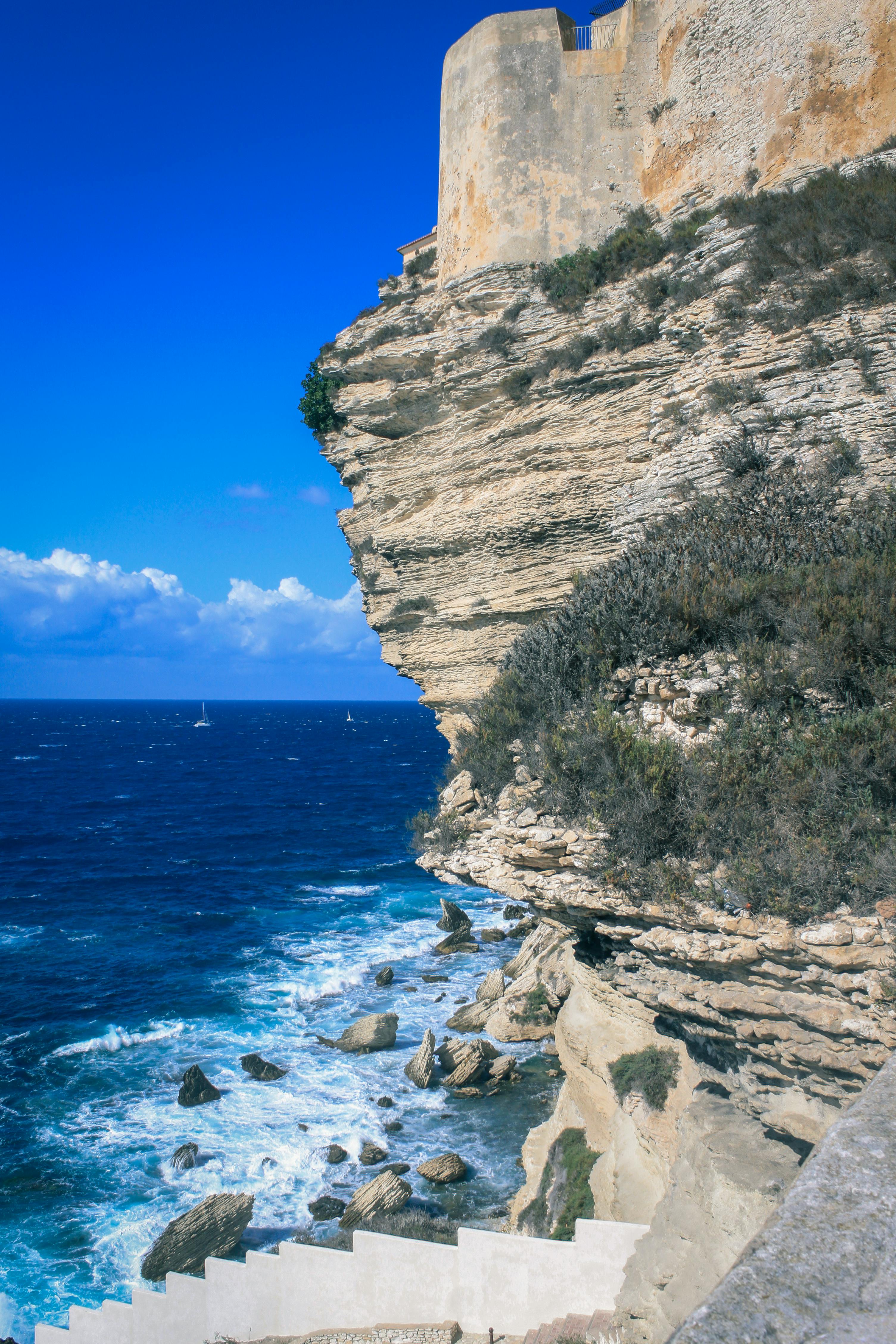 Rock Cliff Near Ocean With Kayakers and Speed Boat Passing · Free Stock ...