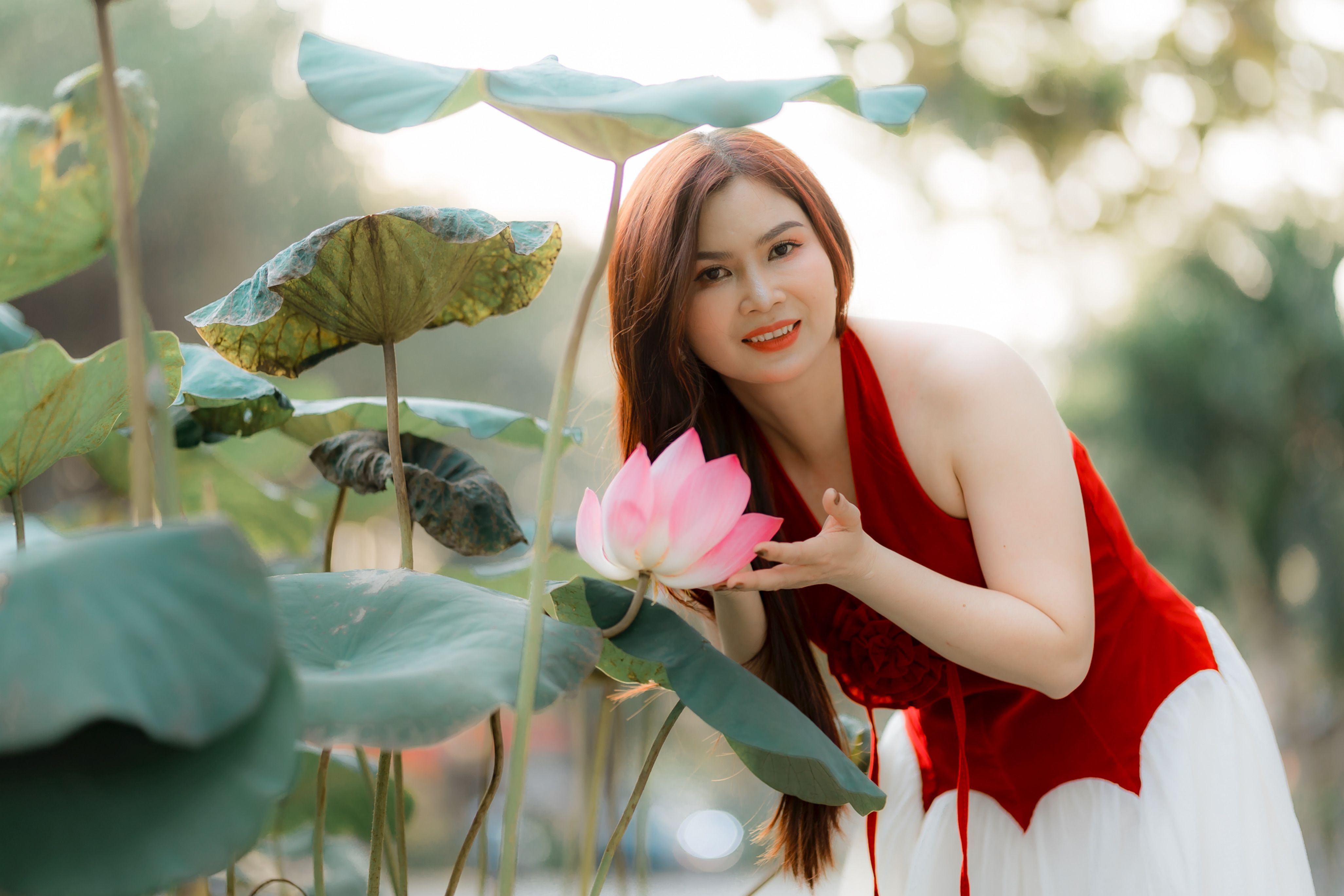 Woman in Red Dress Enjoying Lotus Flower Outdoors · Free Stock Photo