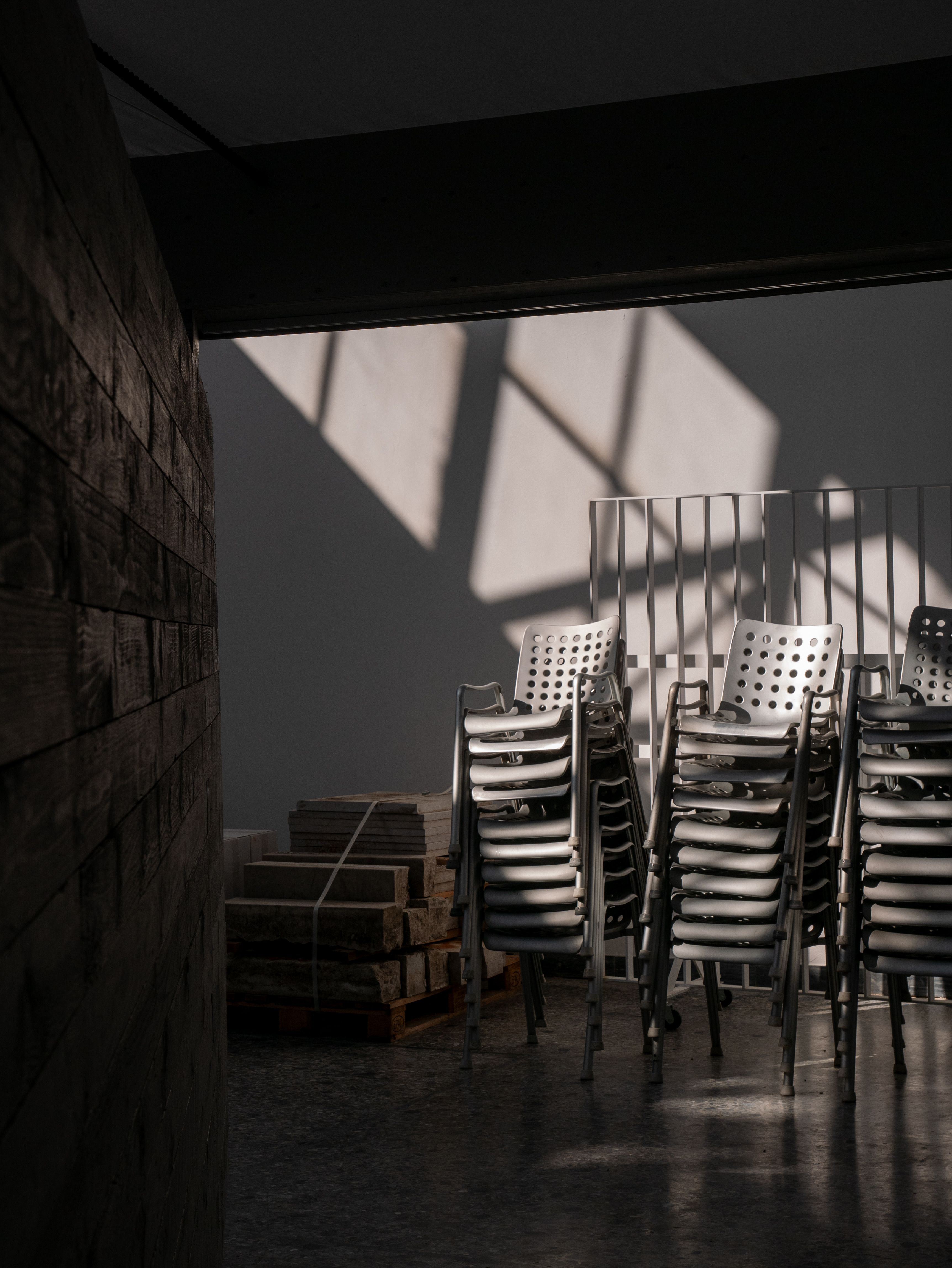 Stacked Metal Chairs in Dimly Lit Room · Free Stock Photo