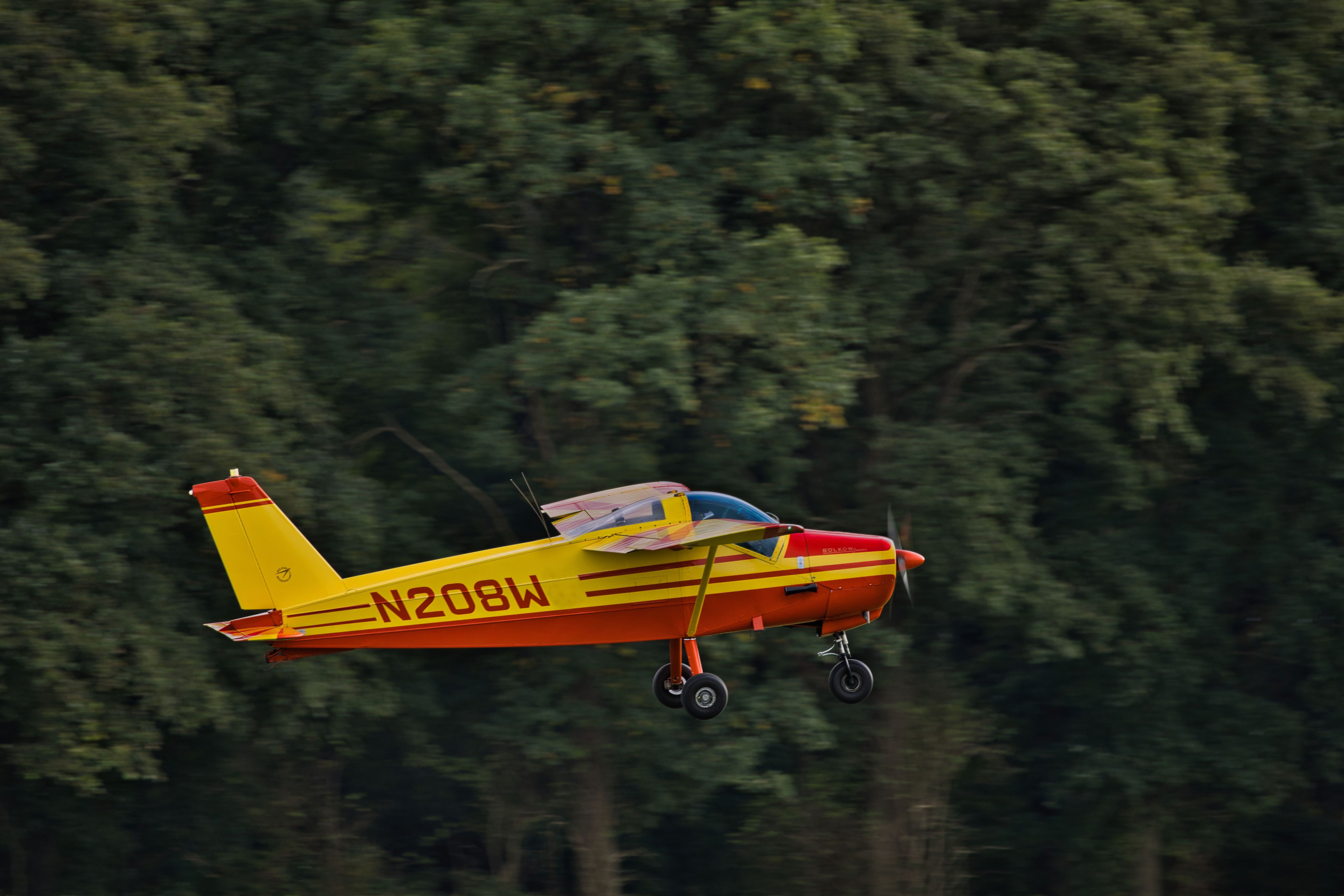 Bright Yellow Airplane Flying Over Forest · Free Stock Photo